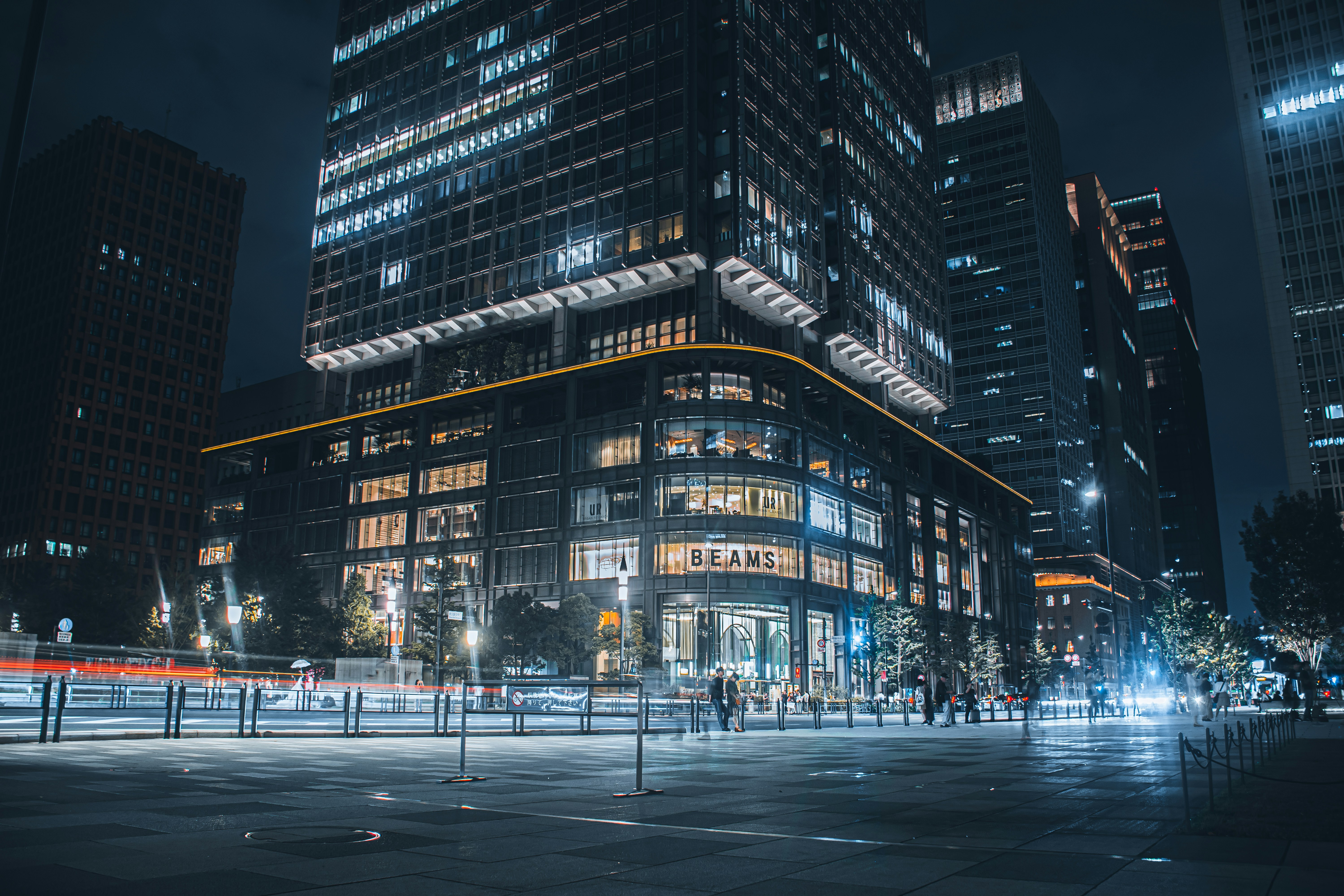 People walking on sidewalk near high rise building during night time ...