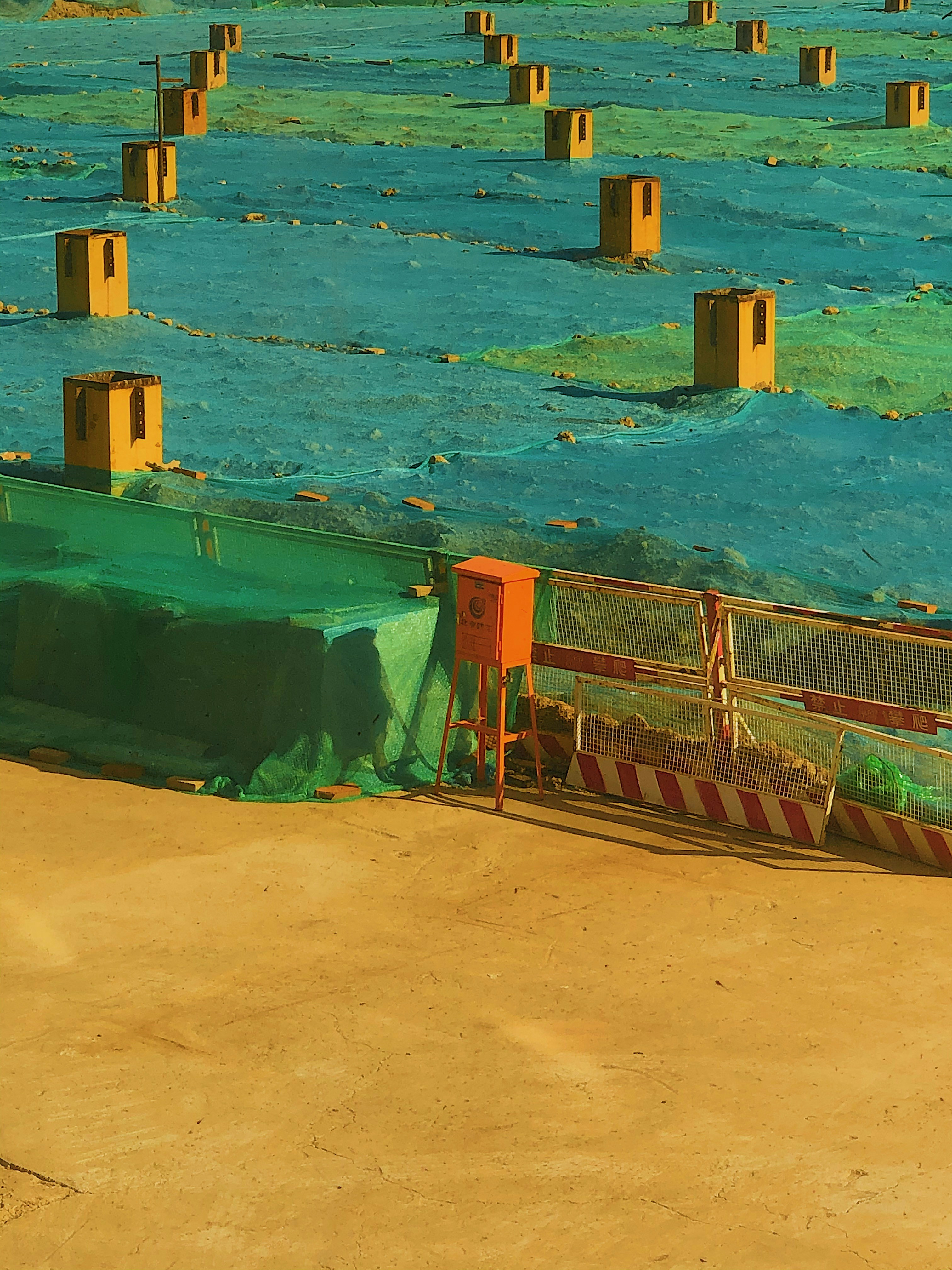 Vibrant construction site featuring a network of blue tarps and orange utility boxes, showcasing organized chaos in urban development.