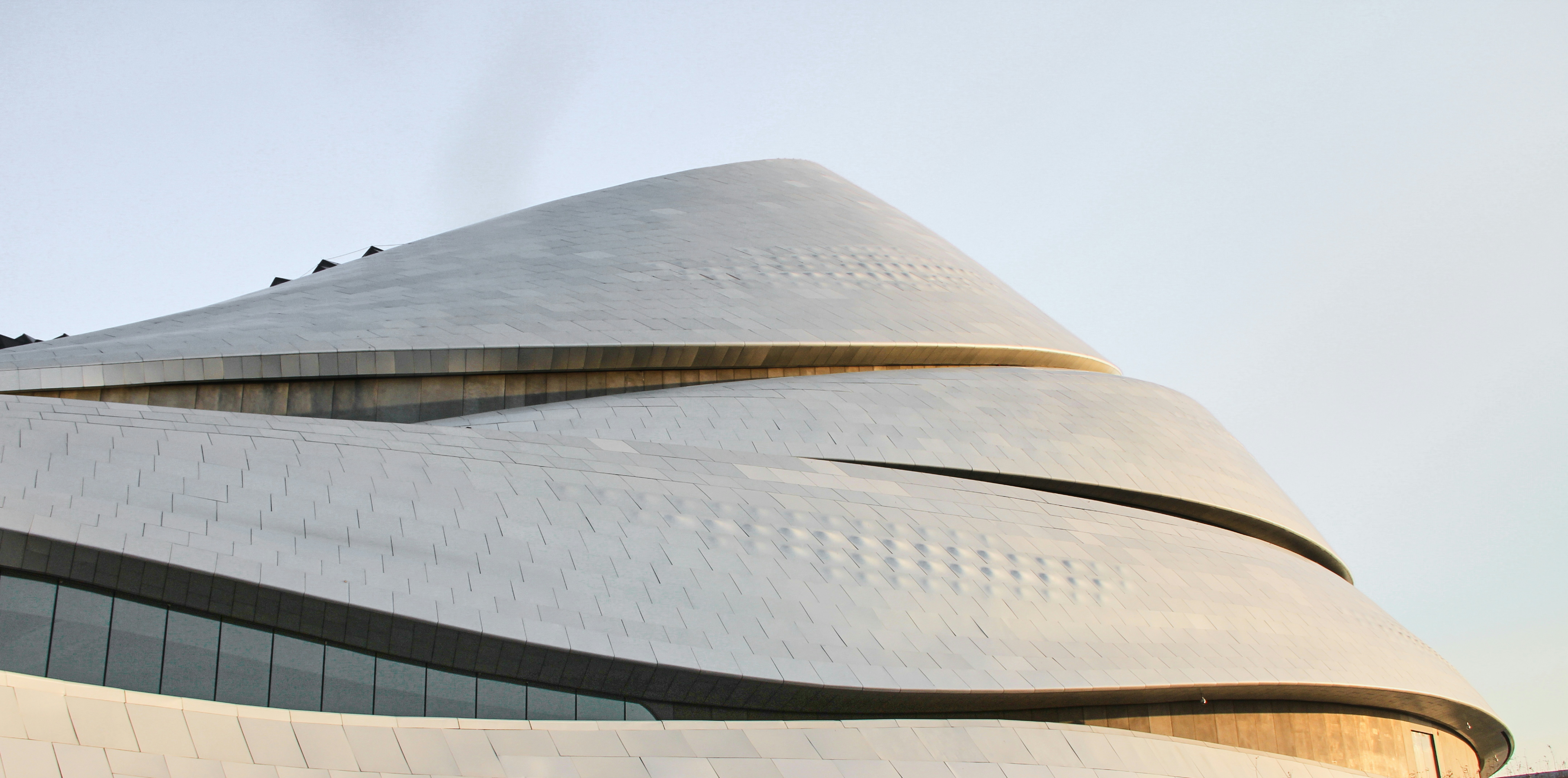 Sleek modern building with smooth, curved lines against a pale sky.