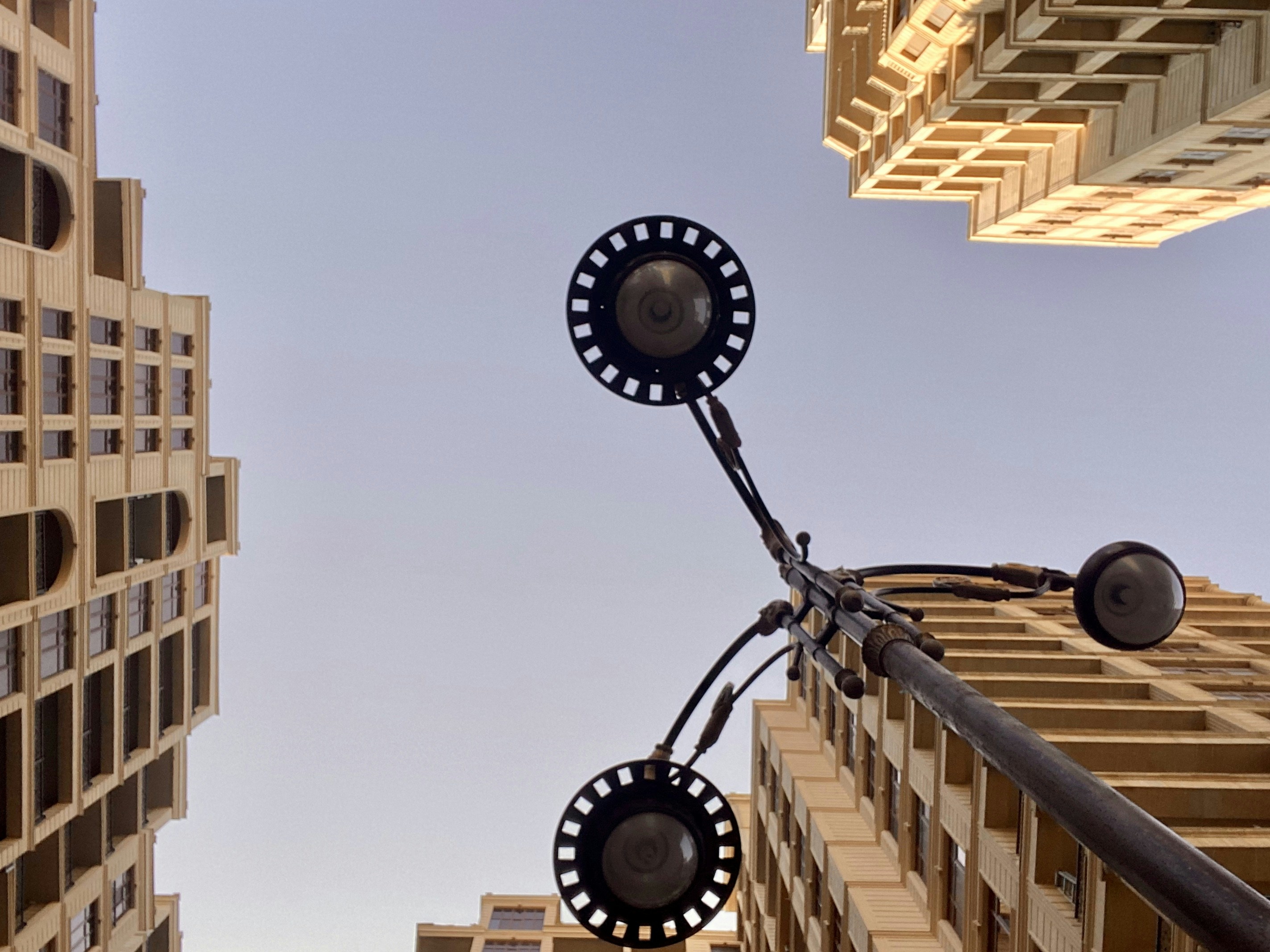 Streetlight framed by towering buildings against a clear blue sky.