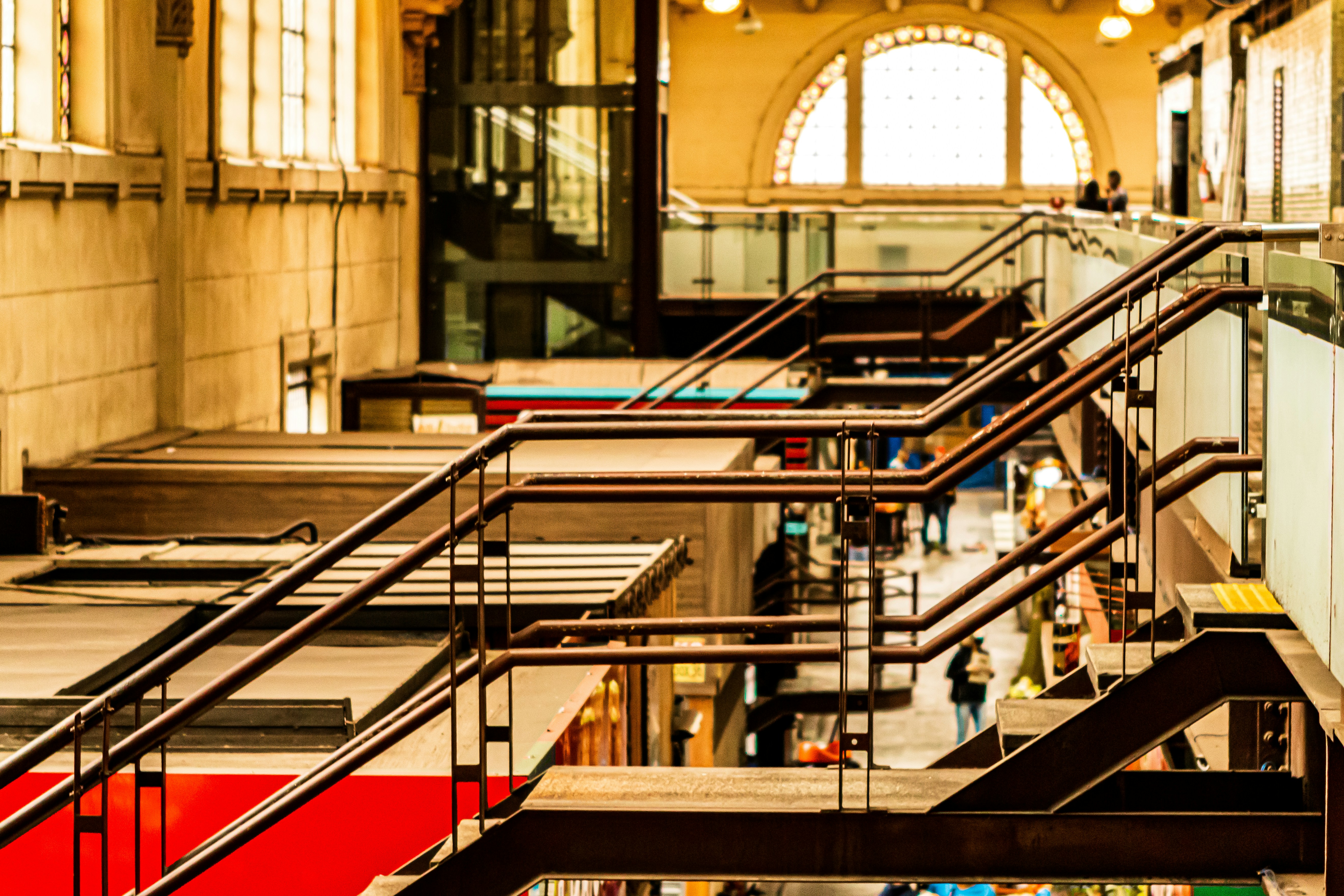 Intricate staircases weave through a vibrant market space, illuminated by natural light streaming through large windows.