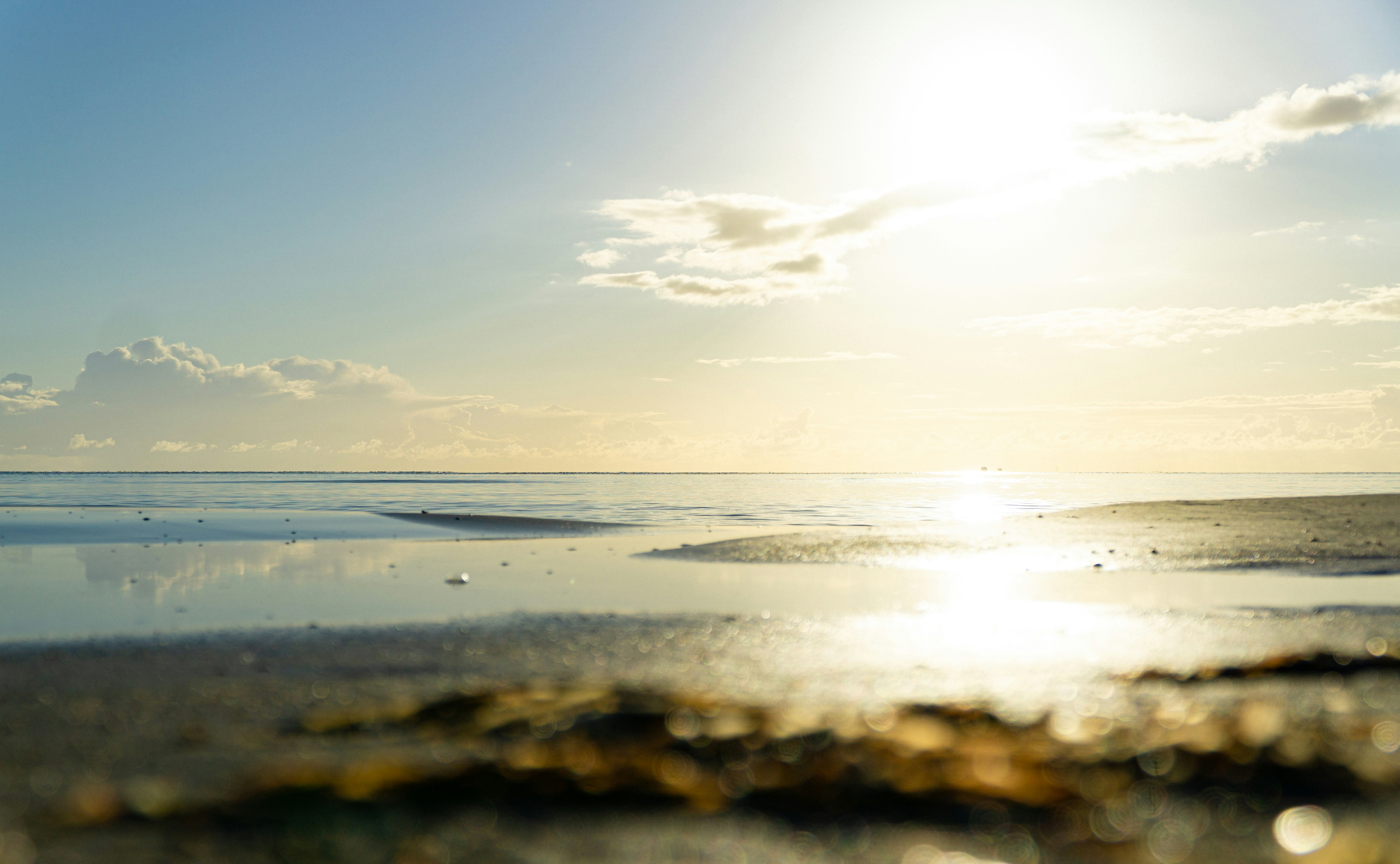 Gentle waves lapping at a sandy shore, illuminated by the soft glow of the setting sun. A tranquil scene capturing the essence of coastal calm.