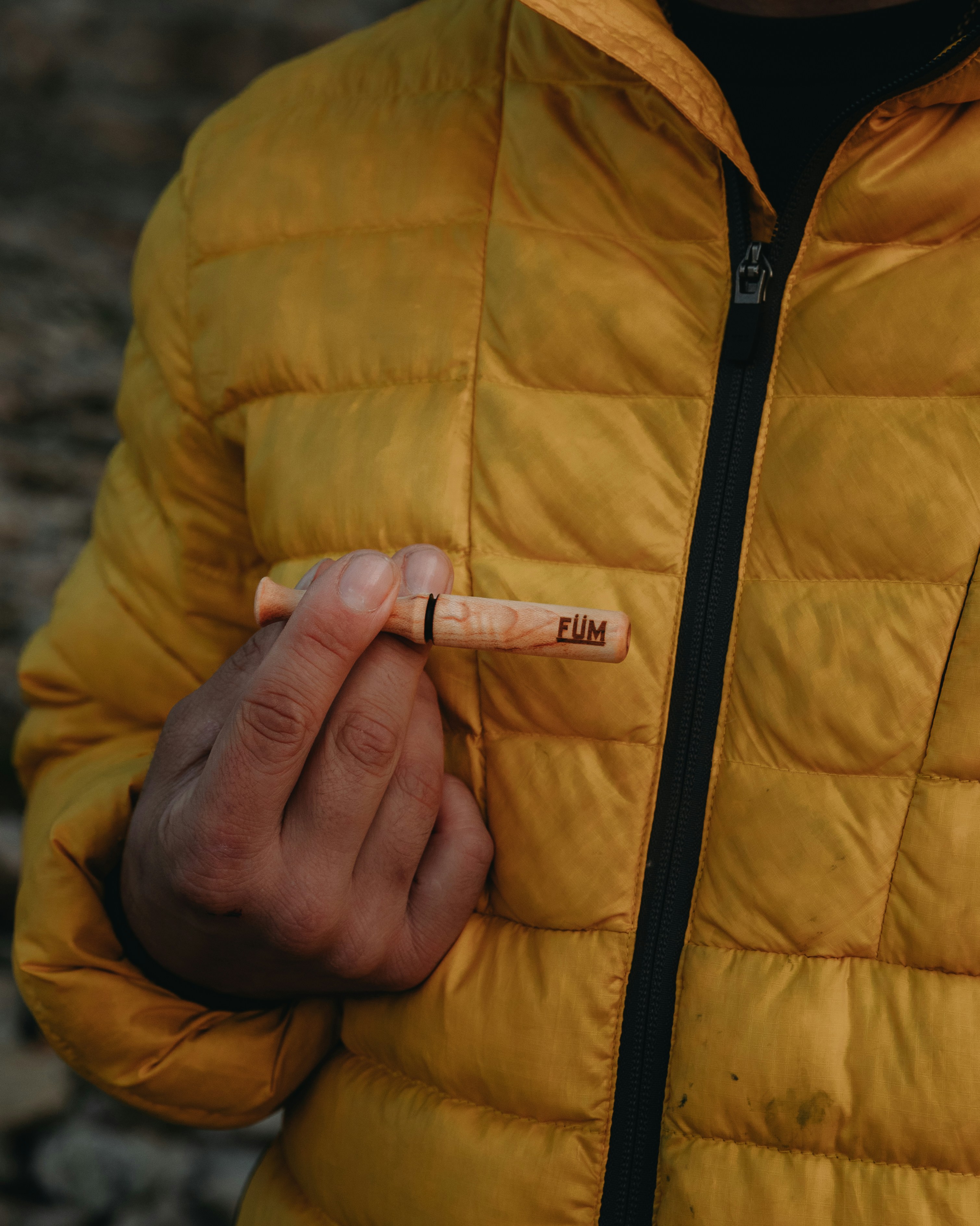 Amber Quilted Moment: A Hand Clutching a Slim Cigarette Against a Dark Brick Background