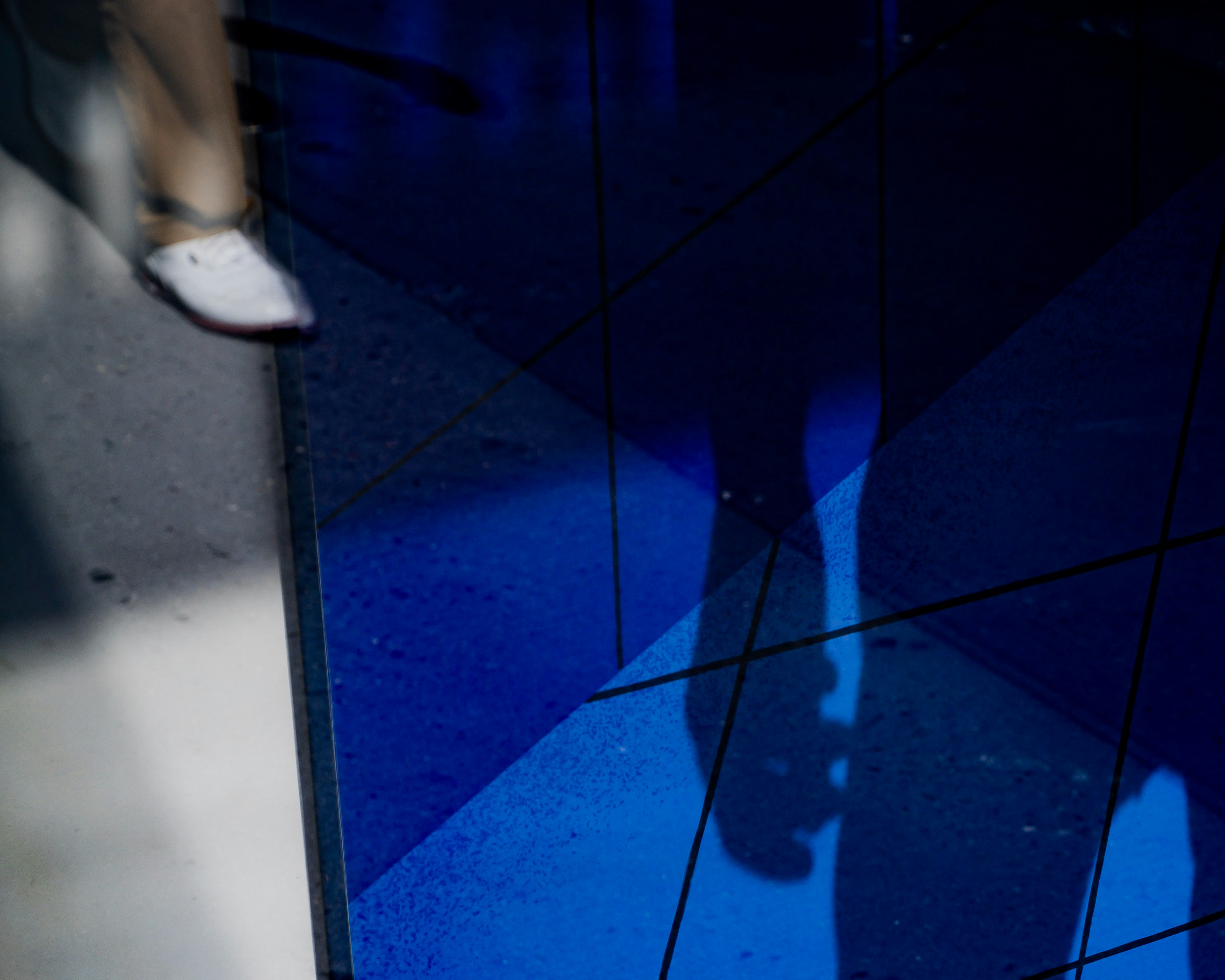 Blue Reflections on Glass: Fragmented Footsteps in a Modern Facade