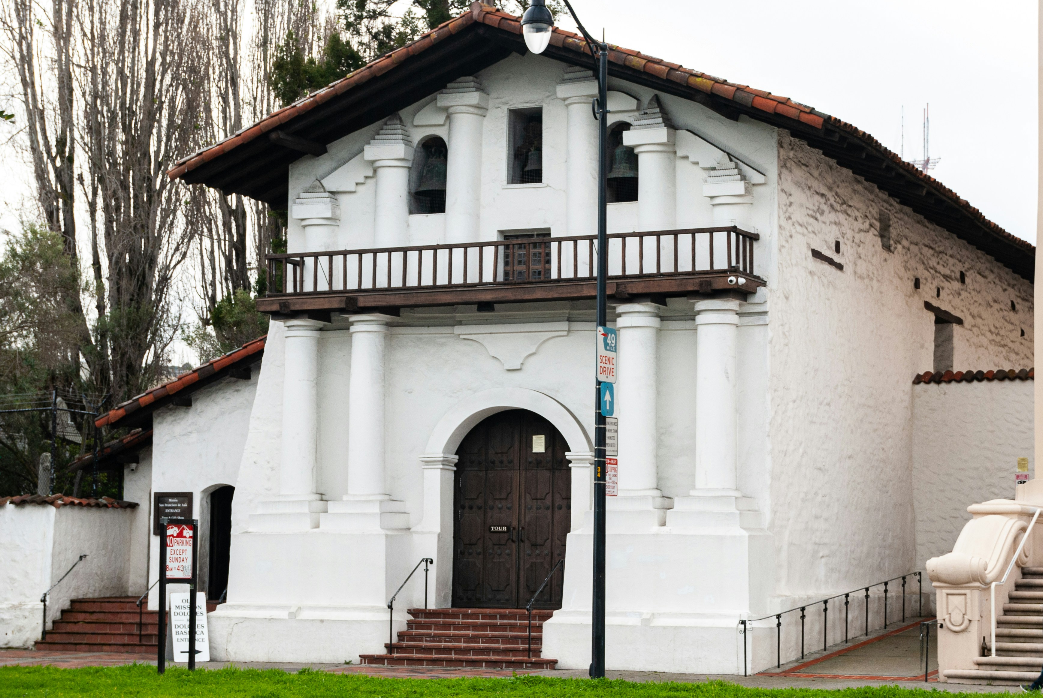 Historic building featuring a grand entrance with a wooden door and classic architectural elements, surrounded by lush greenery.