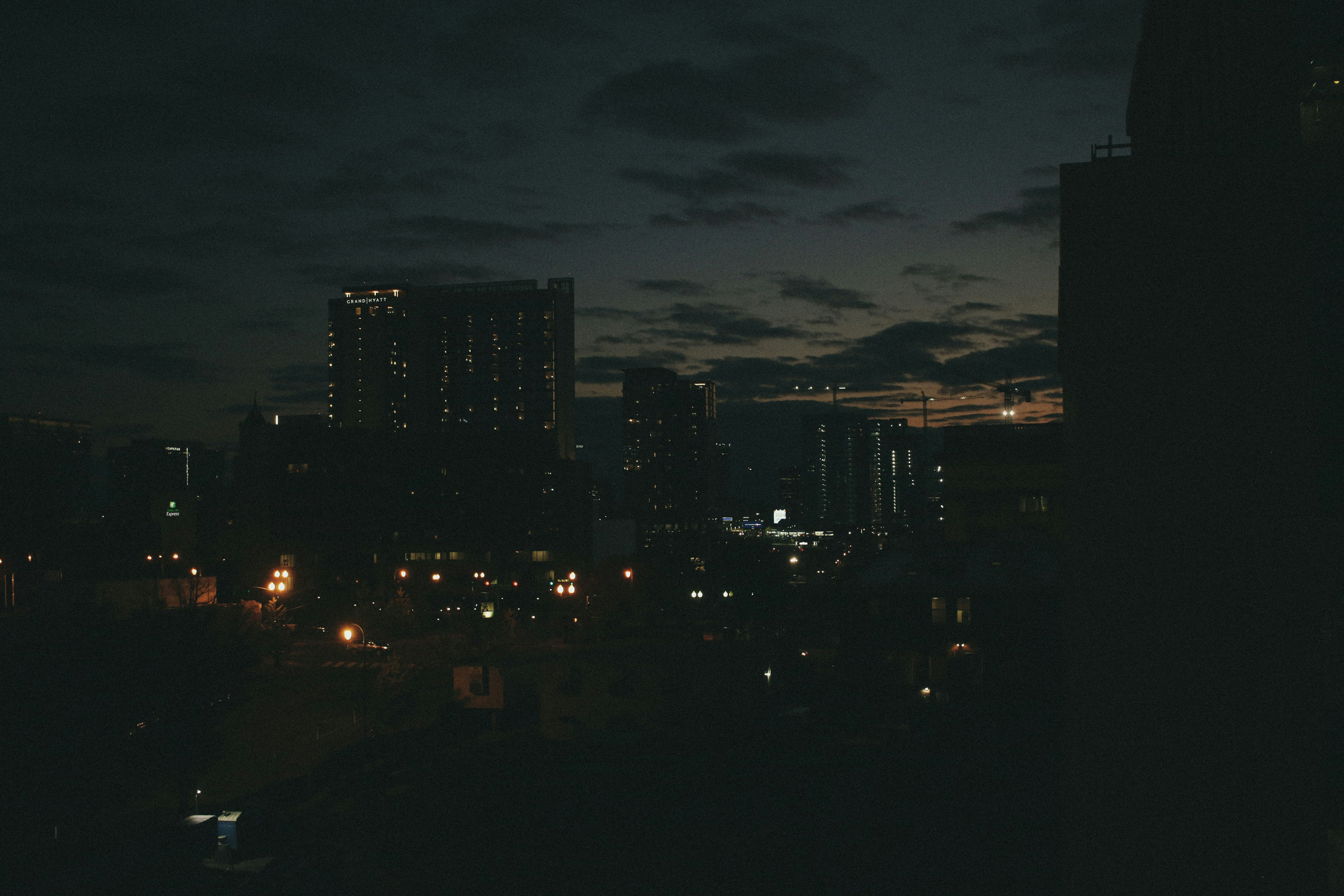 City skyline with illuminated buildings under a twilight sky.