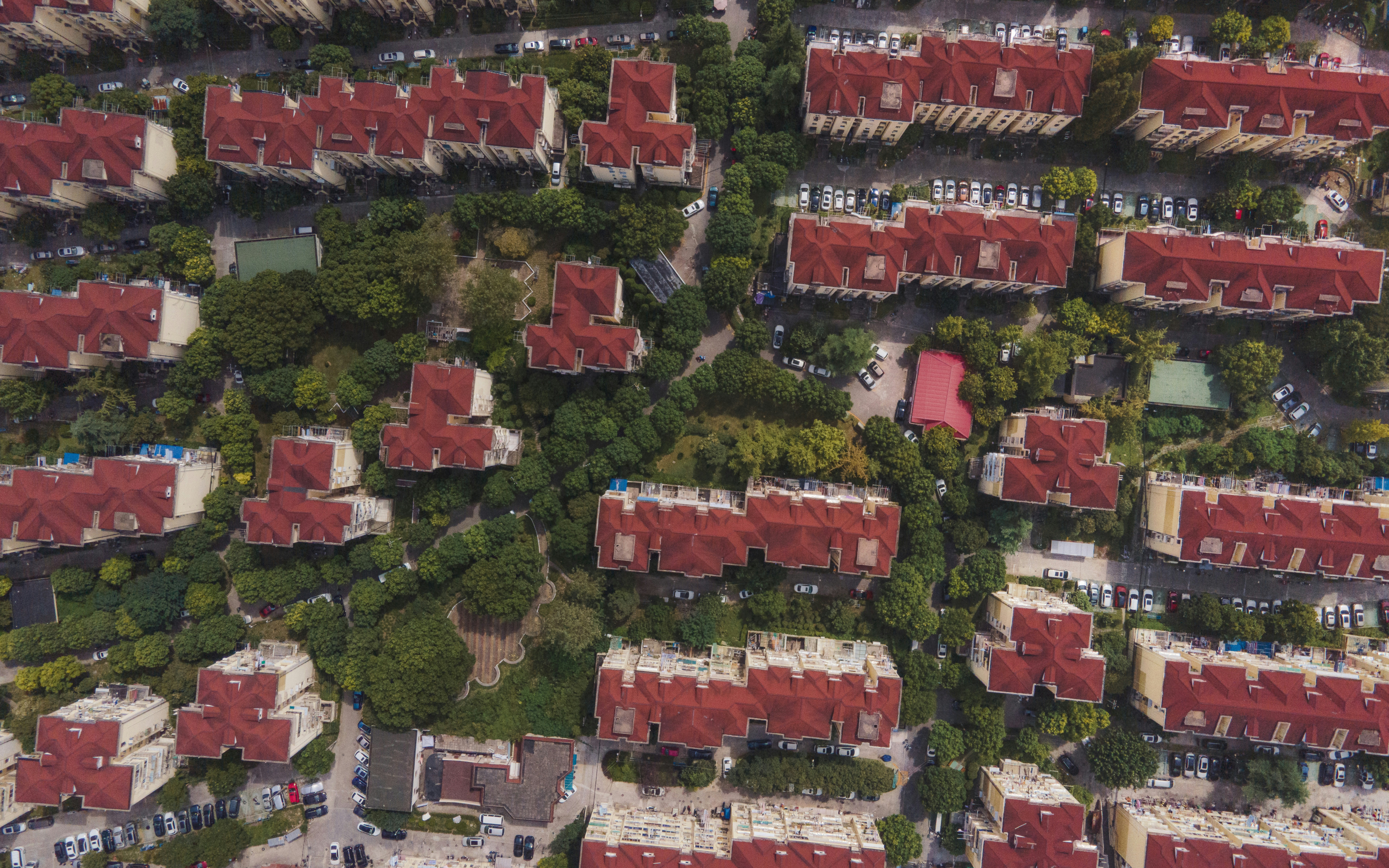 Aerial view showcasing a residential complex with red-roofed buildings surrounded by lush greenery and organized pathways.