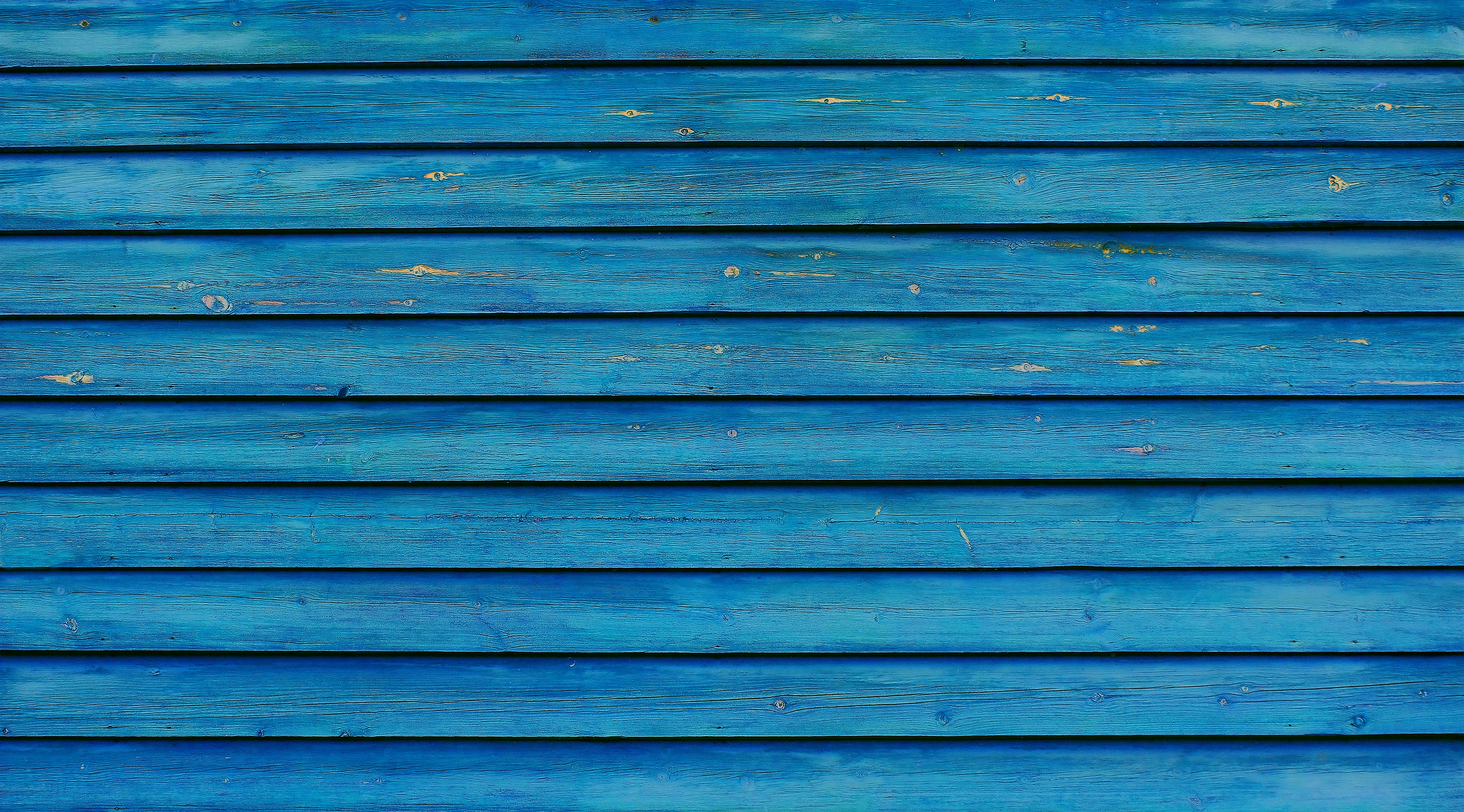 Vibrant blue wooden planks arranged horizontally, showcasing natural textures and weathering effects.