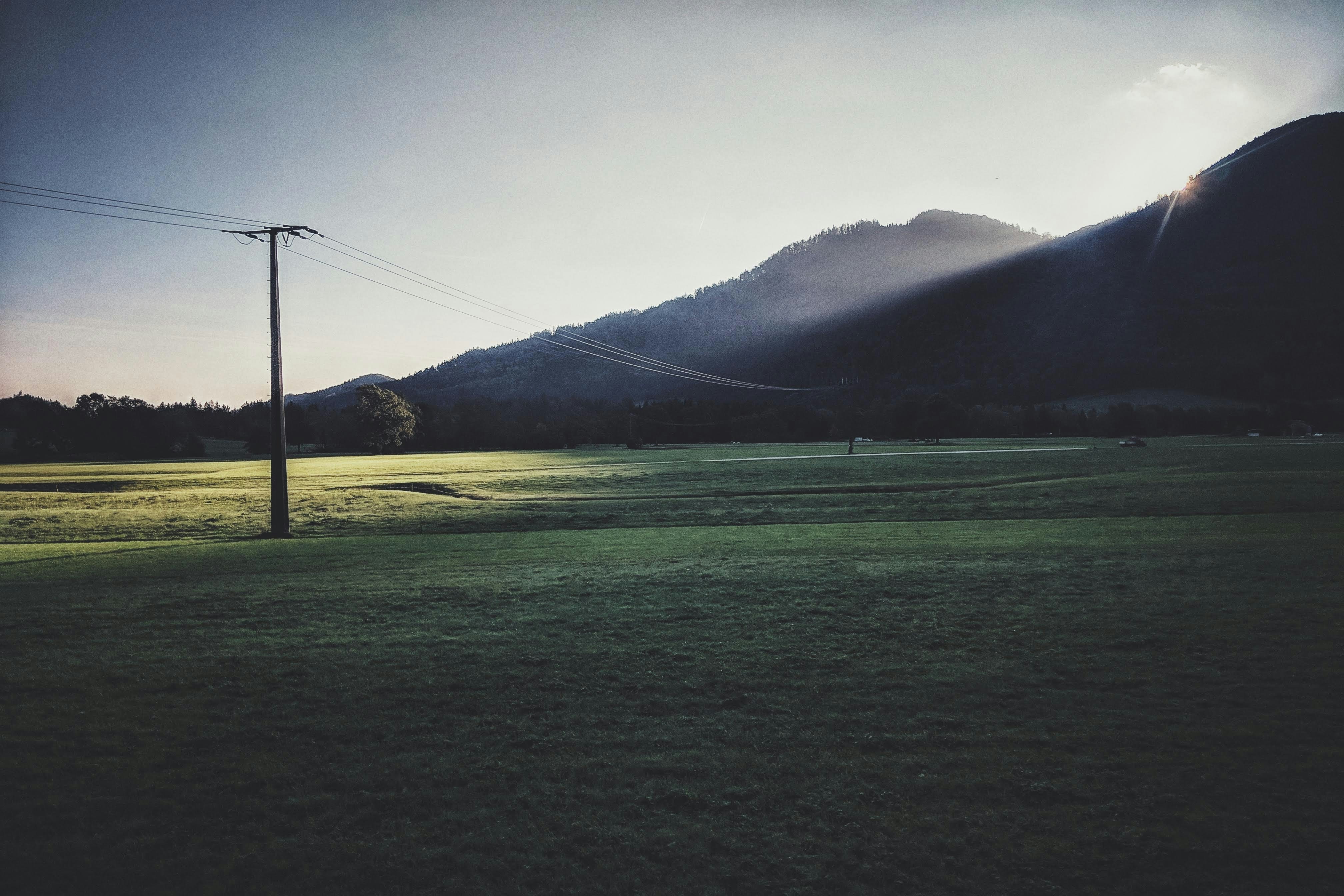 Powerline Quiet: Sunlit Field Below a Shadowed Ridge