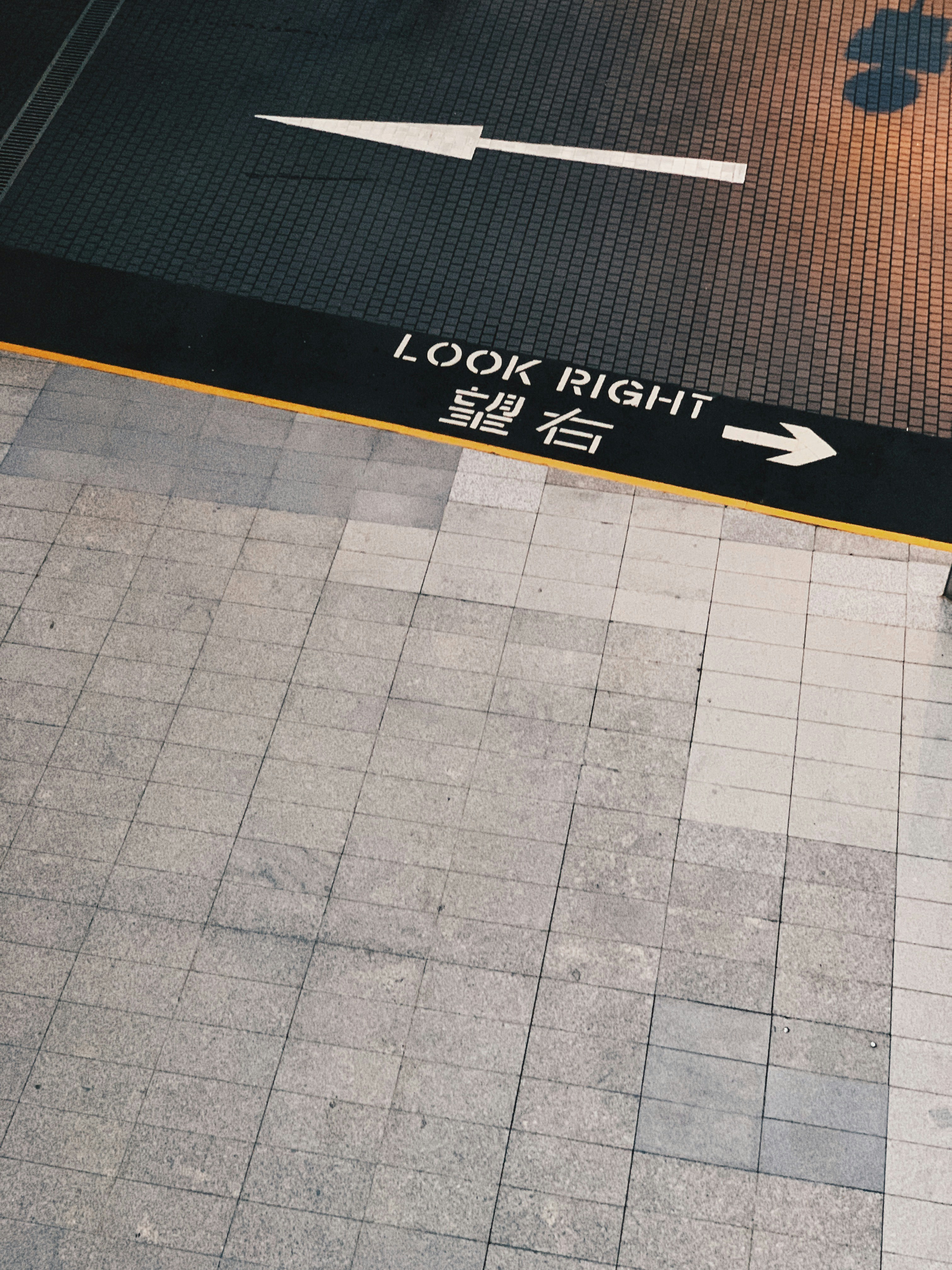 a person walking down a sidewalk next to a look right sign