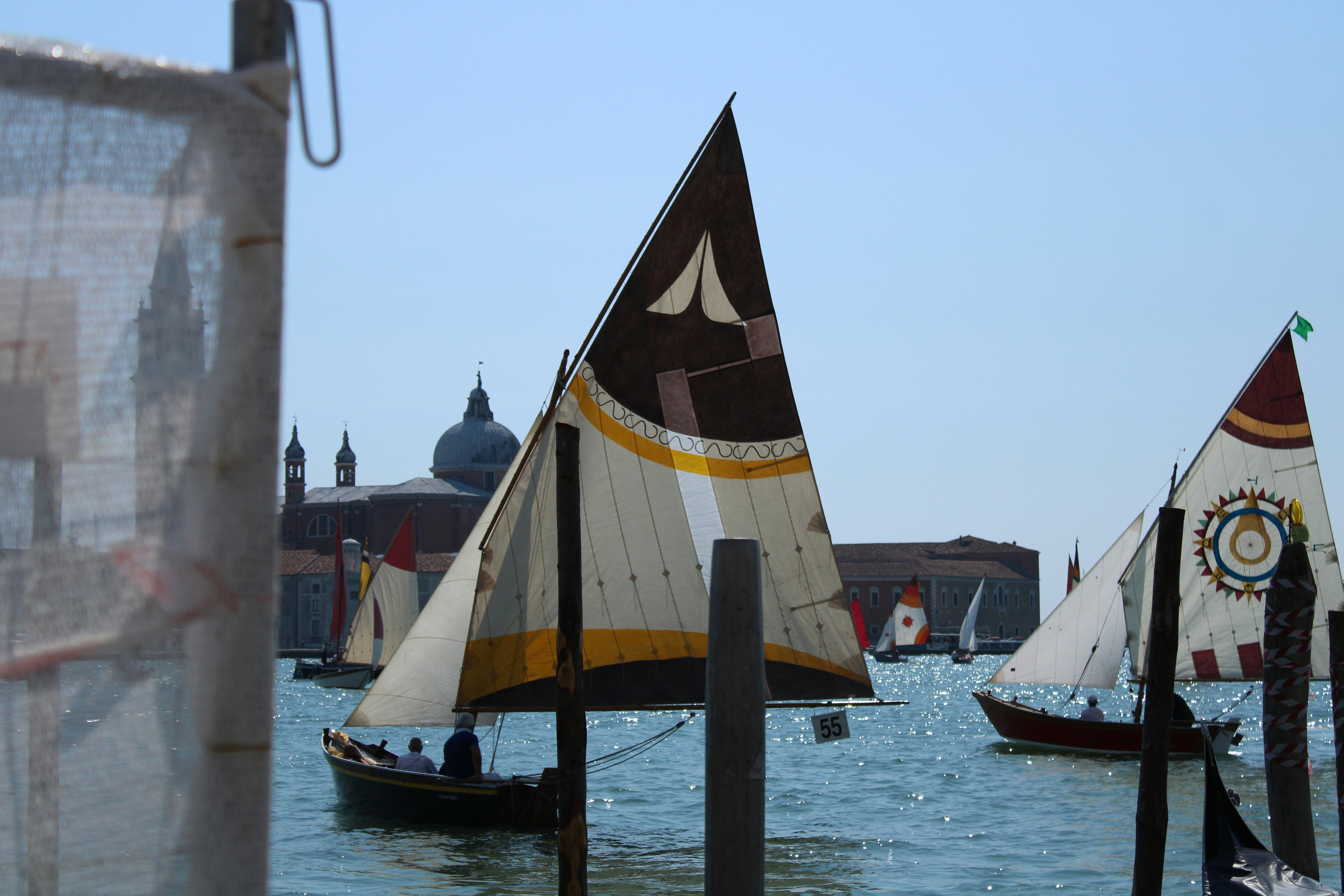 Triangular Sails in a Quiet Harbor: A Sunlit Waterway Scene
