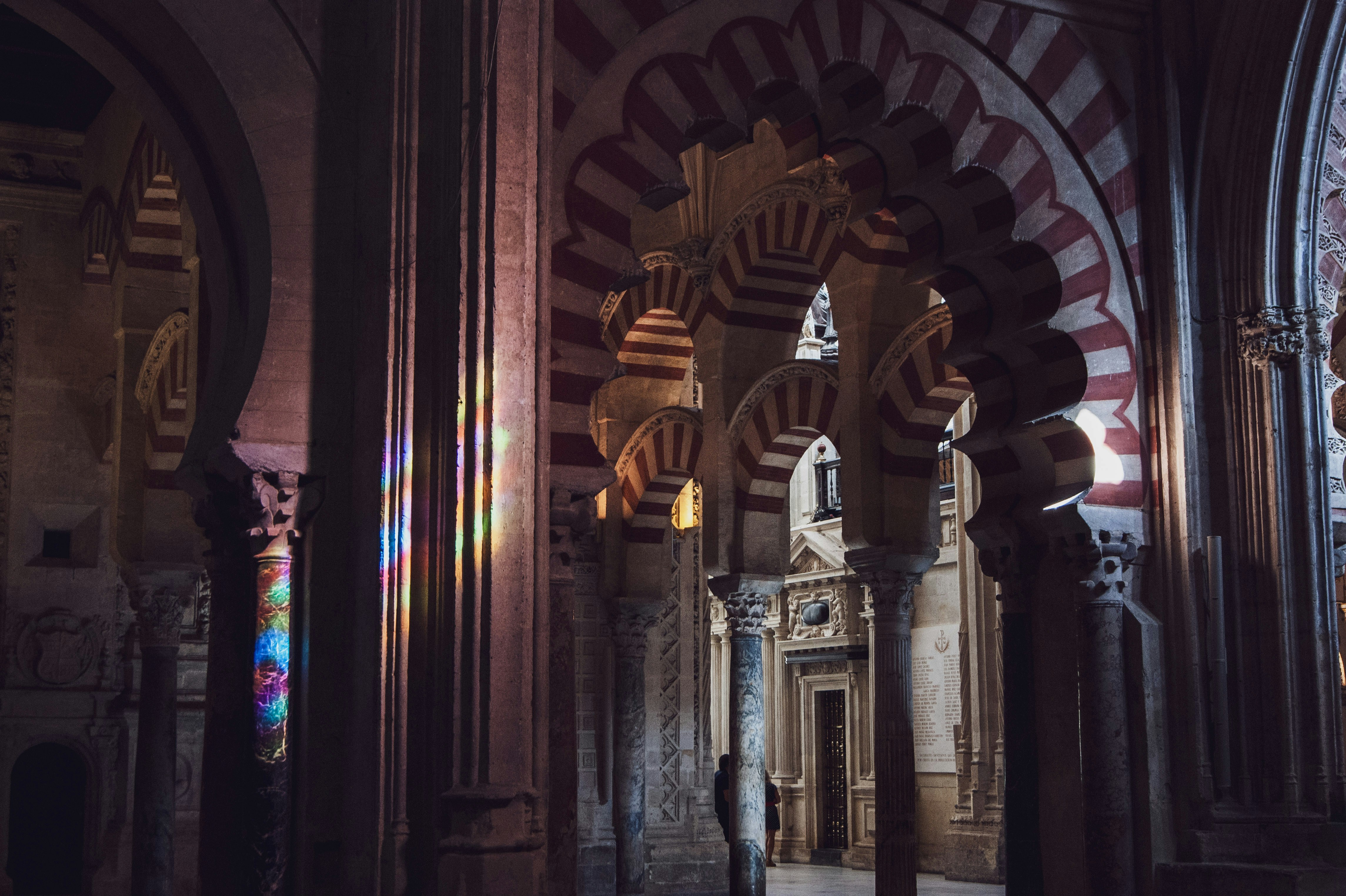 Intricate arches with alternating red and white stripes in dimly lit historic architecture.