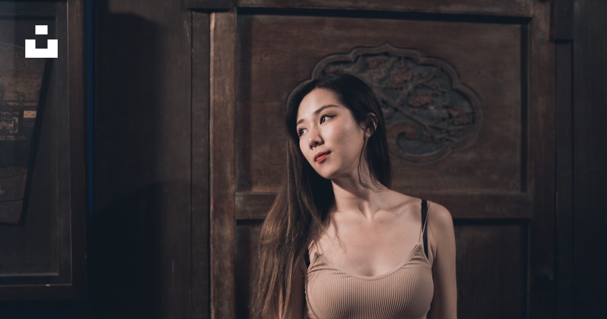 흰색 스파게티 스트랩 탑에 갈색 나무 문 근처에 서 있는 여자 사진 Unsplash의 무료 의복 이미지