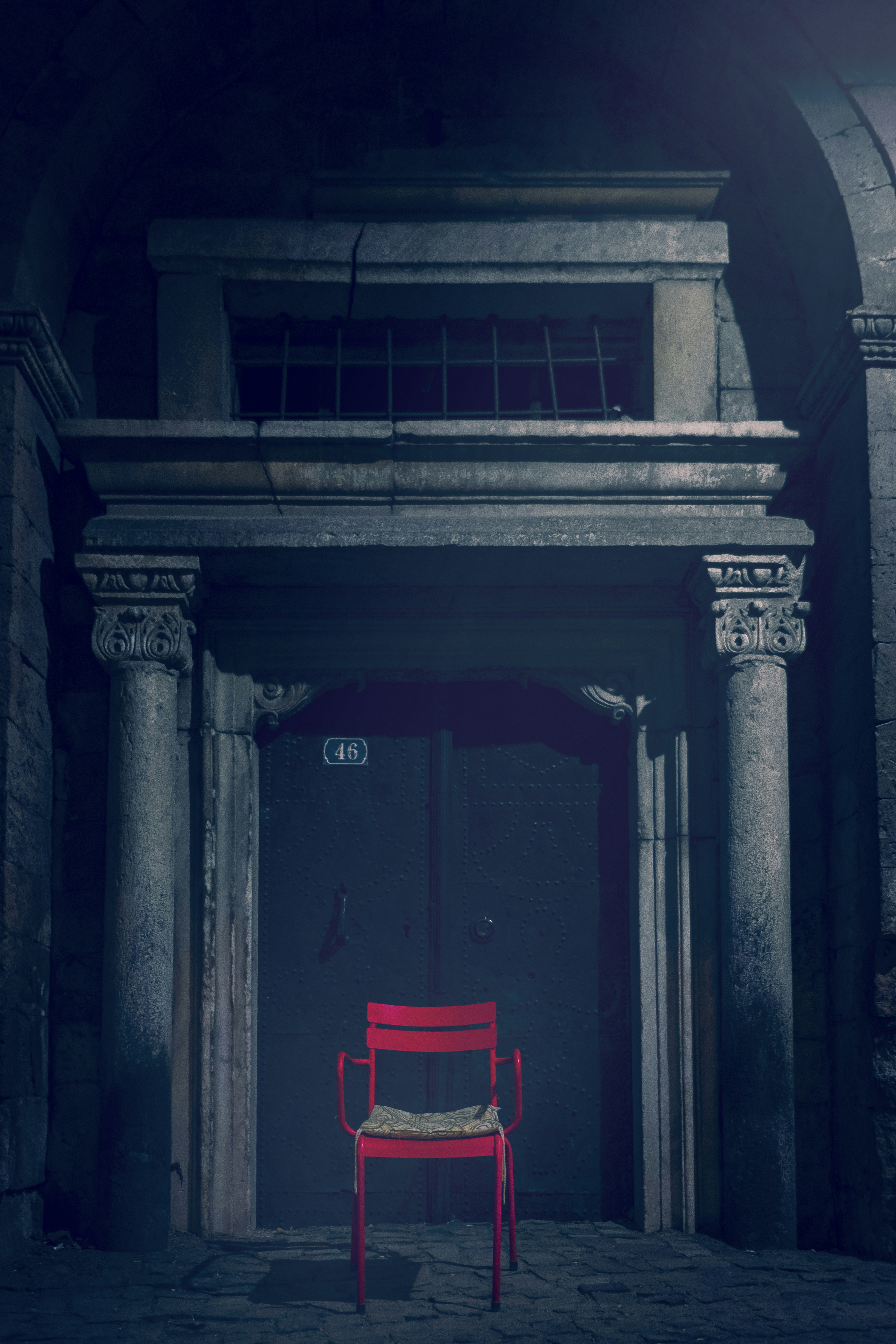 Red Chair in a Quiet Doorway: A Solitary Accent in Dusky Stone