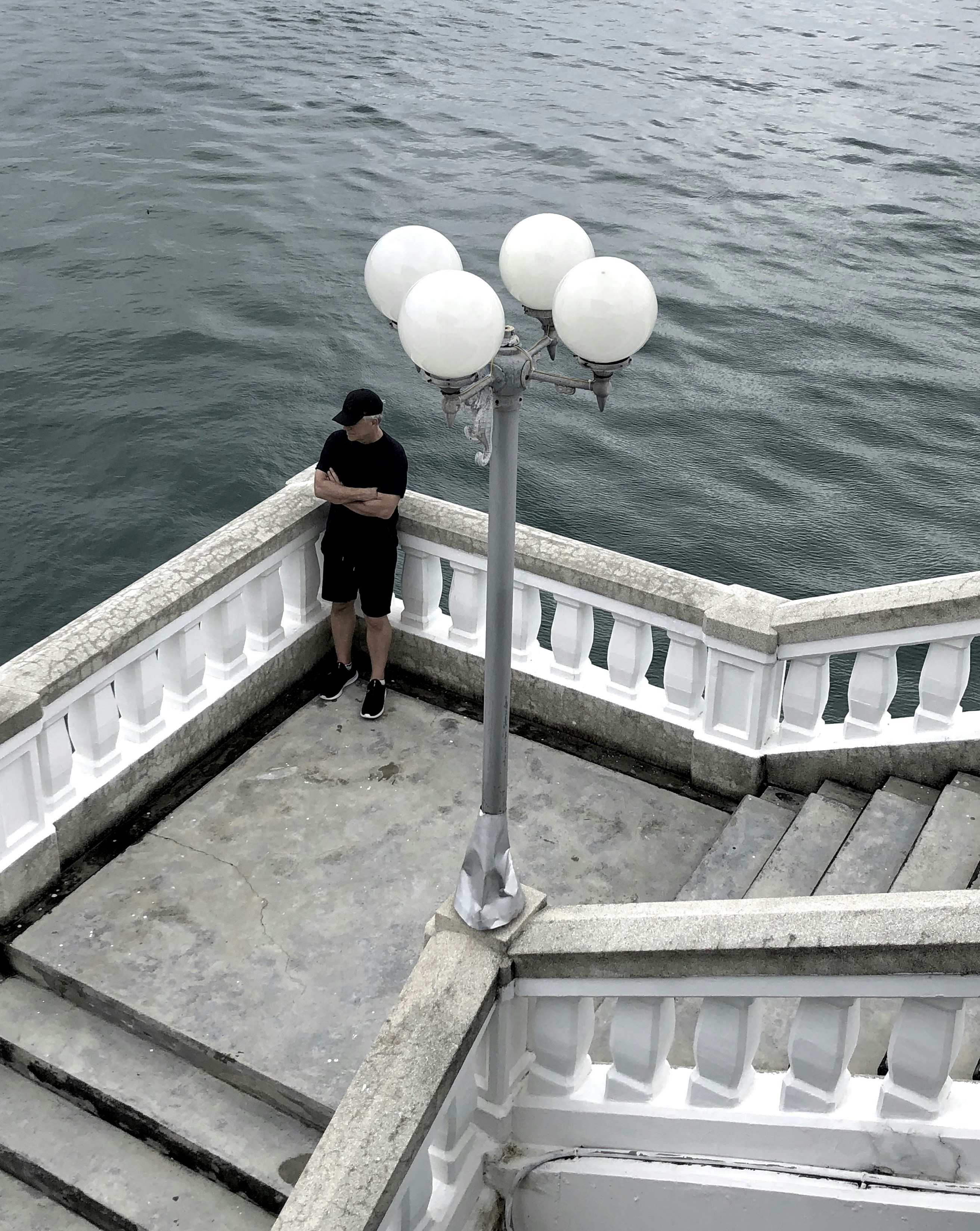 Globe-Lit Terrace: Solitary Figure on a Sea-View Staircase