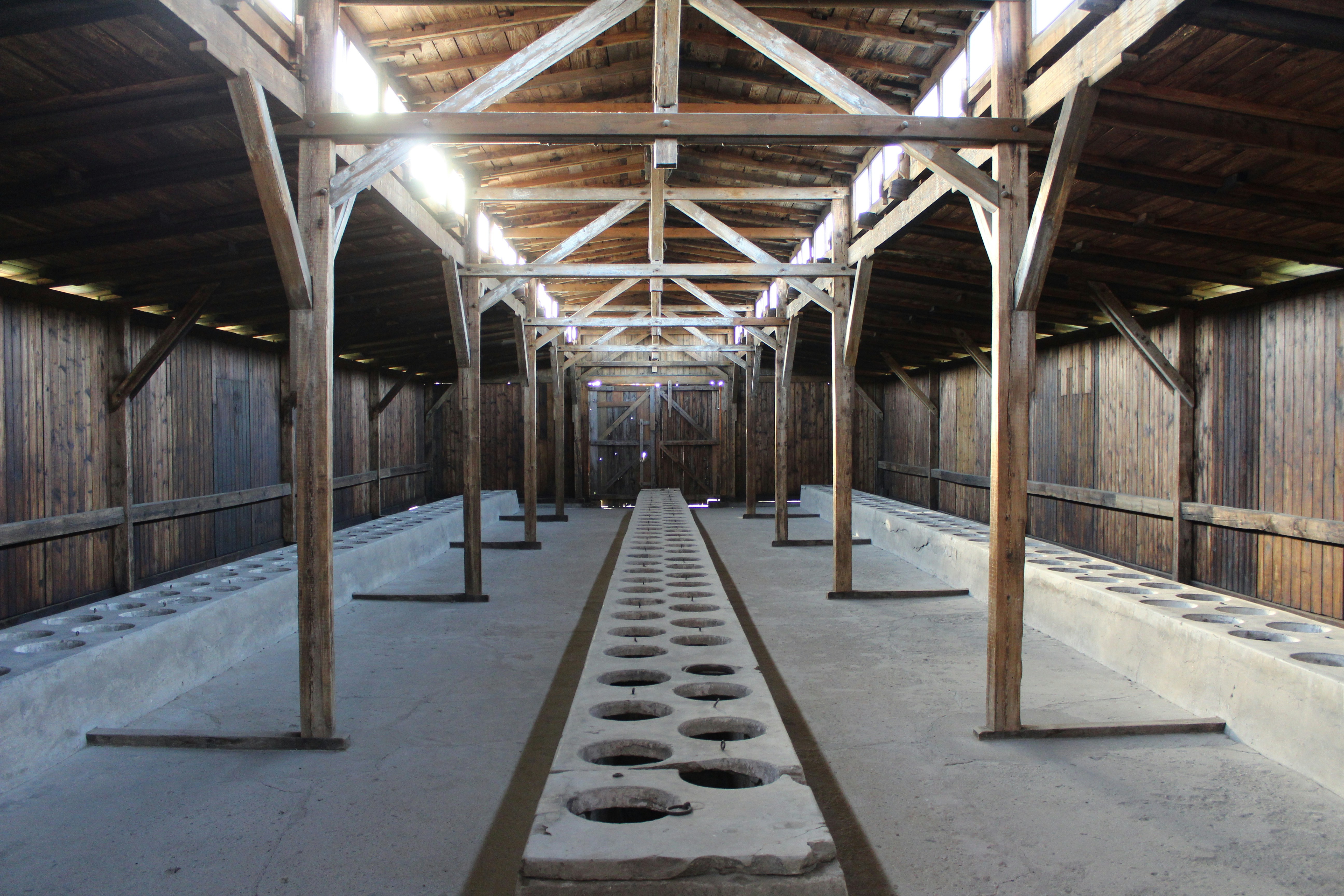 Wooden-beamed interior of a historical industrial building with symmetrical rows and circular floor openings.