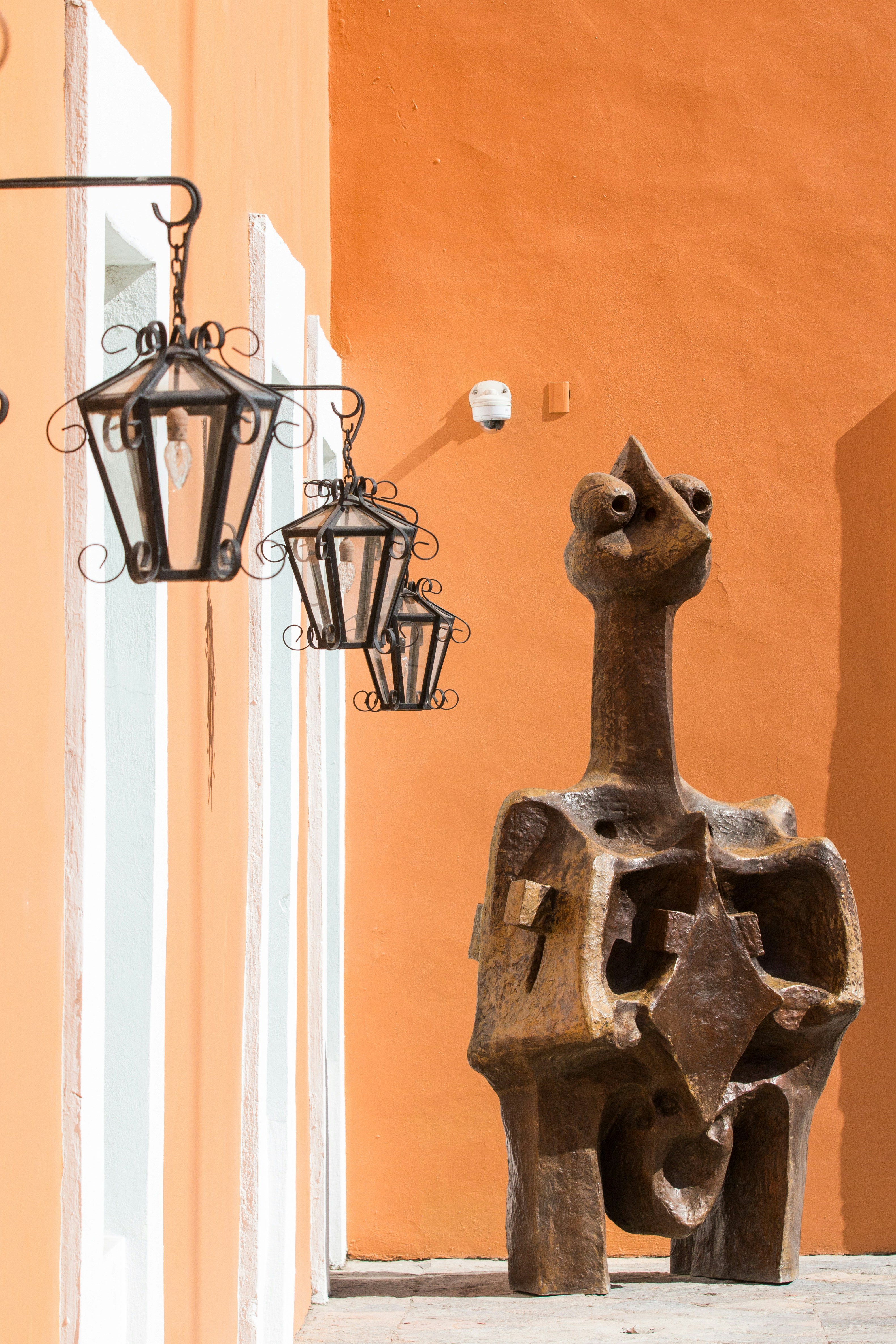 Sunlit Coral Facade: An Abstract Stone Figure Between Lanterns