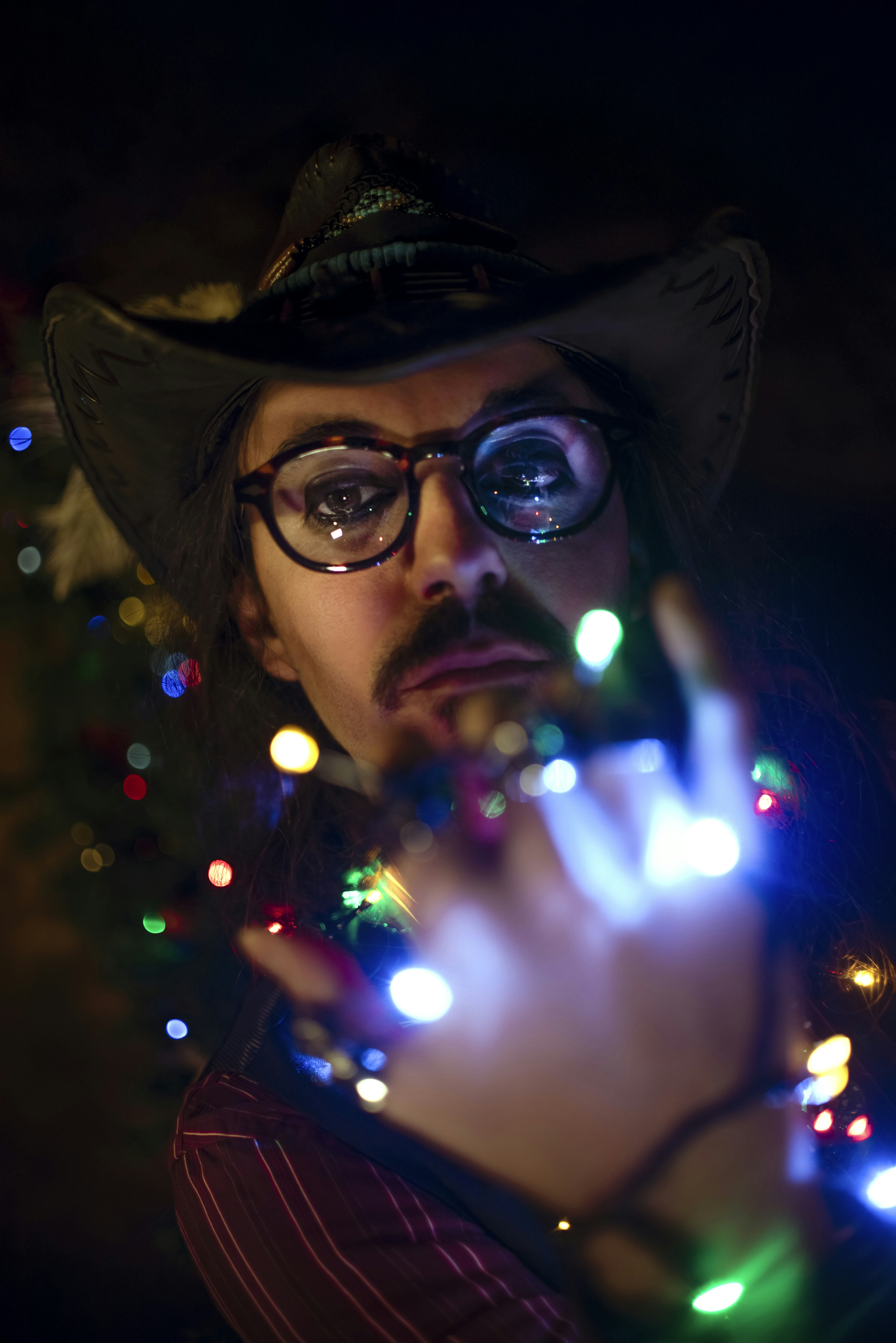 Neon Reach in Velvet Night: A Hat-Wearing Portrait Reaching for the Holiday Glow