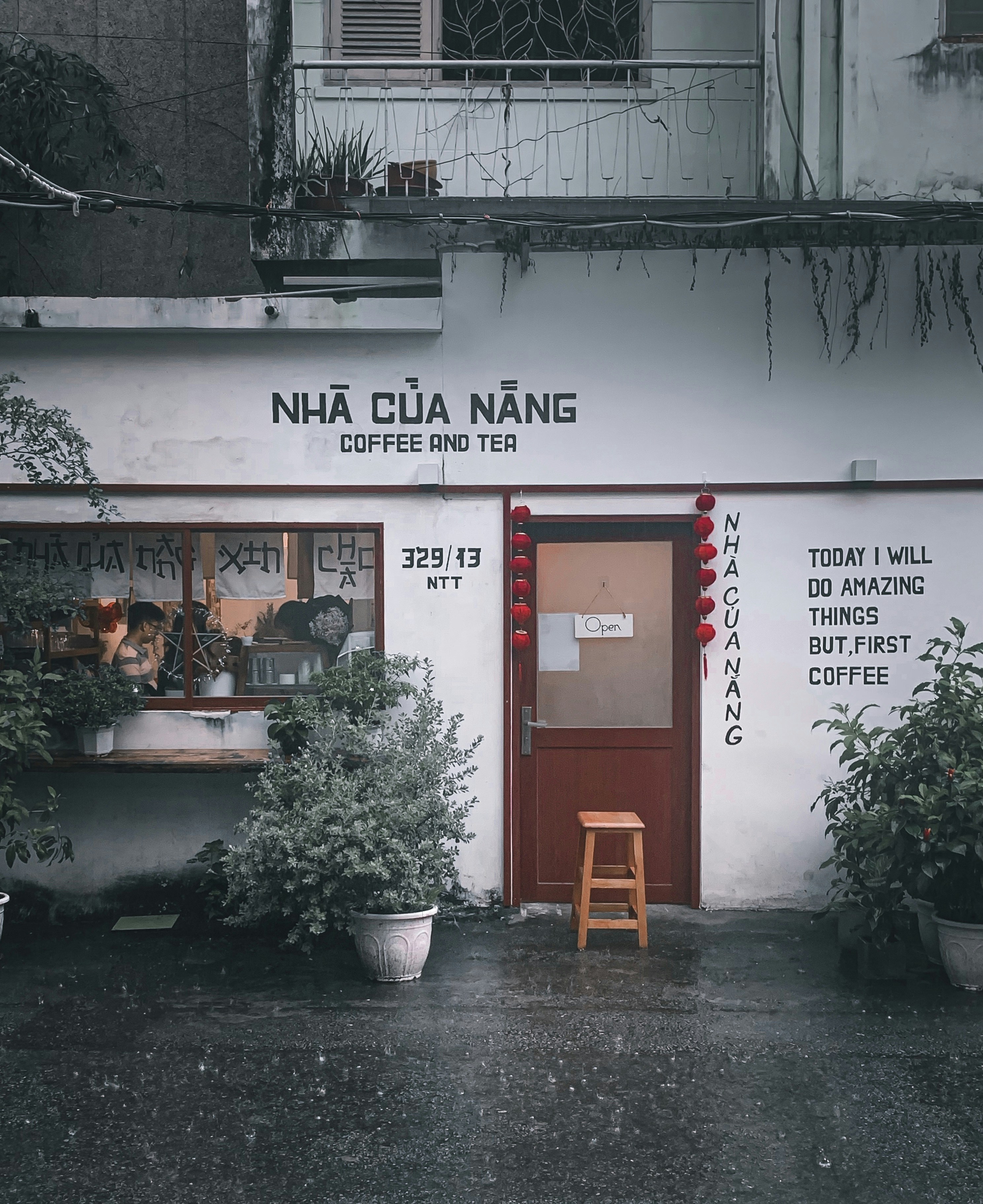 Cozy coffee shop exterior with welcoming signage and lush greenery, inviting patrons to enjoy a warm beverage. The atmosphere suggests a blend of relaxation and community.