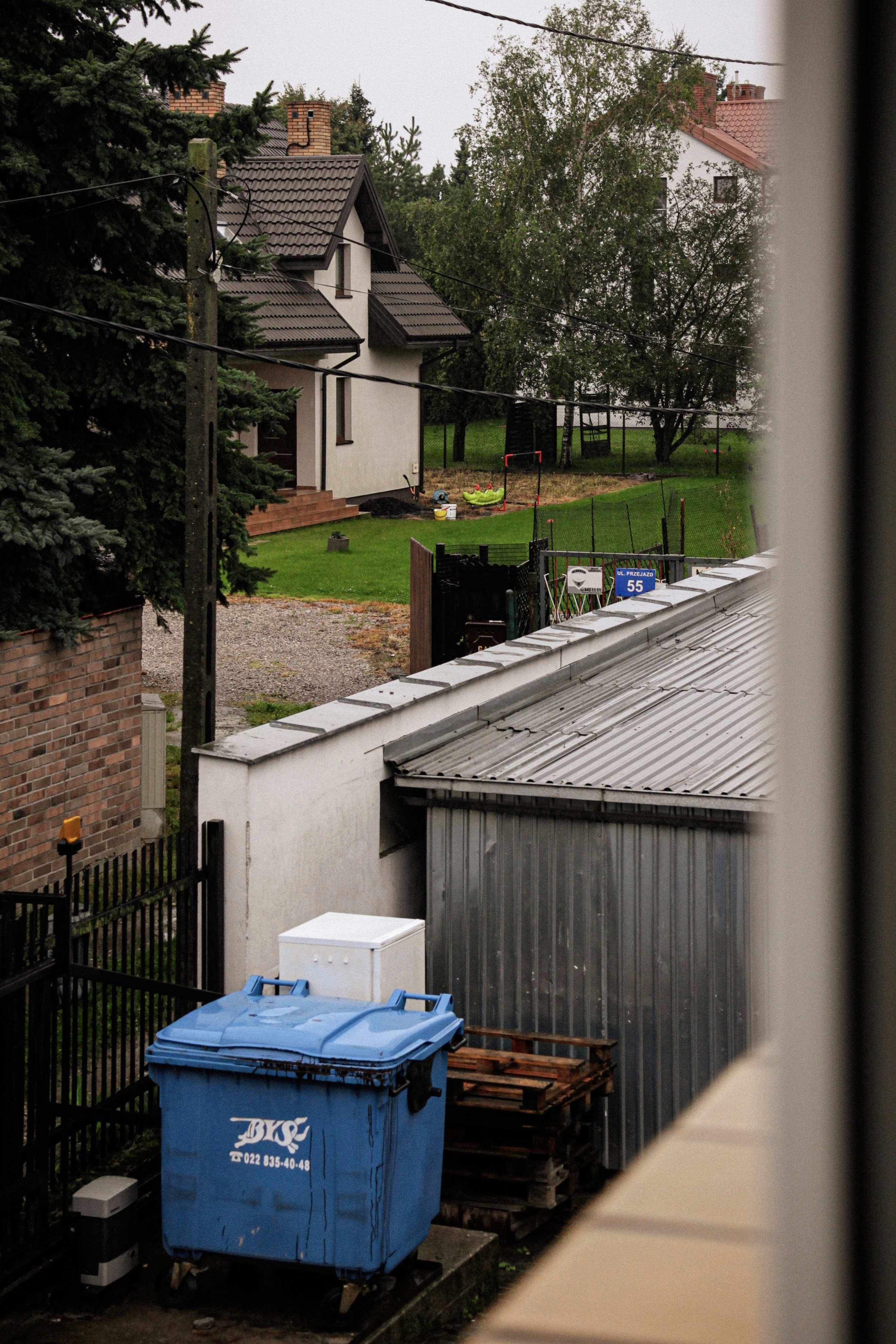 Blue Dumpster Framed by a Quiet Suburban Backlot
