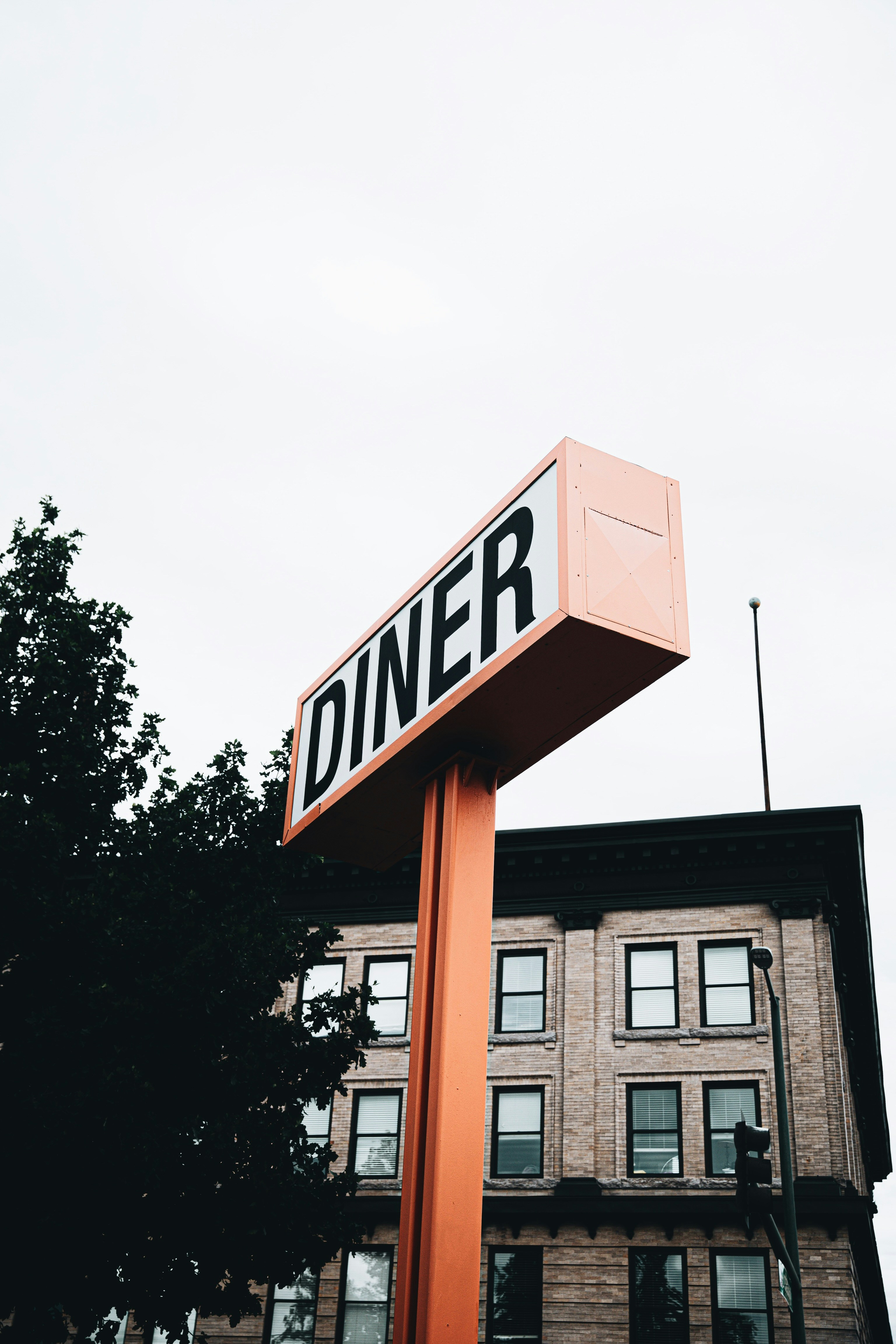 Orange Diner Sign Stands Bold Above an Urban Brick Facade