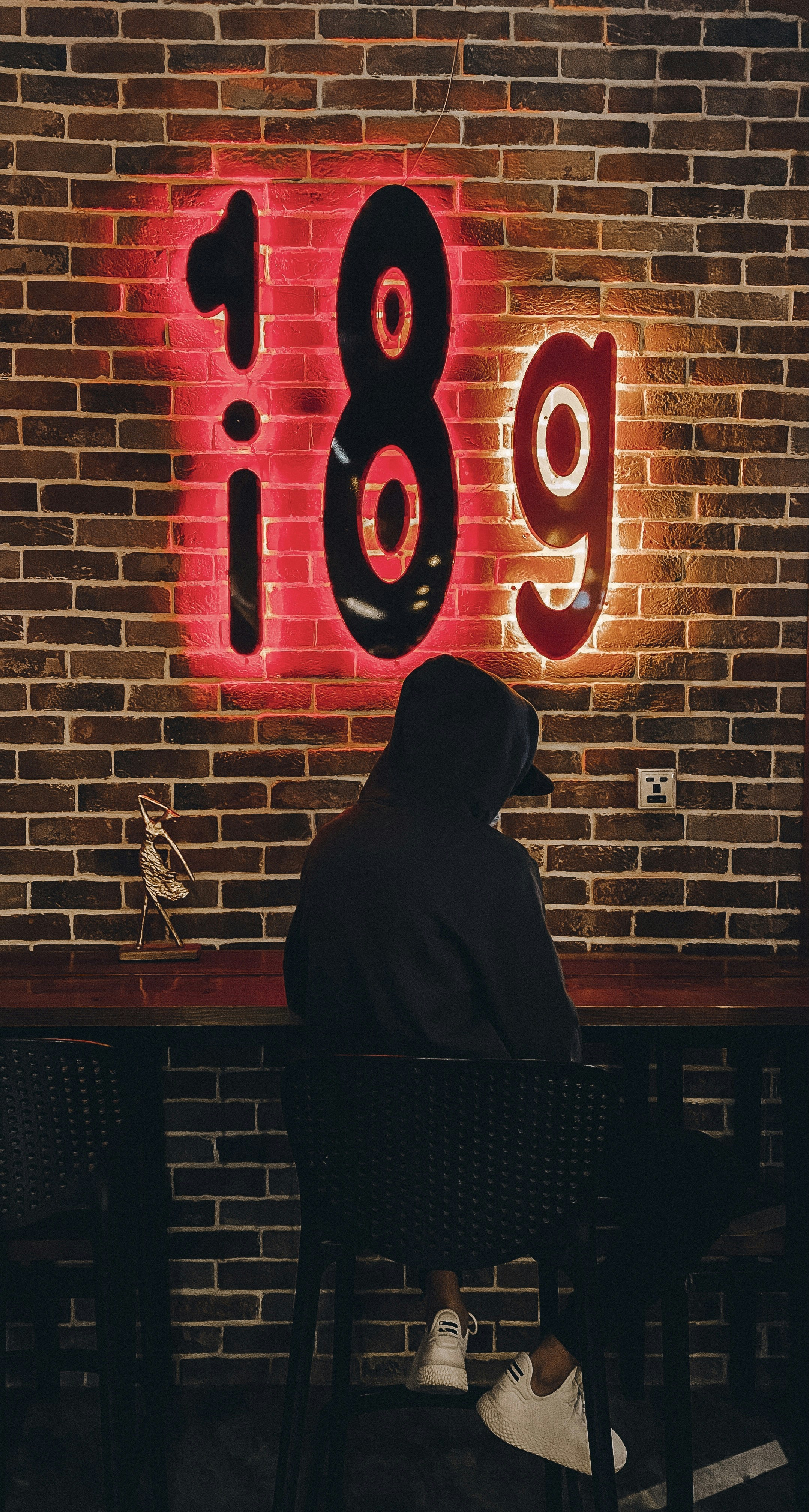 person in black hoodie standing near red and white wall