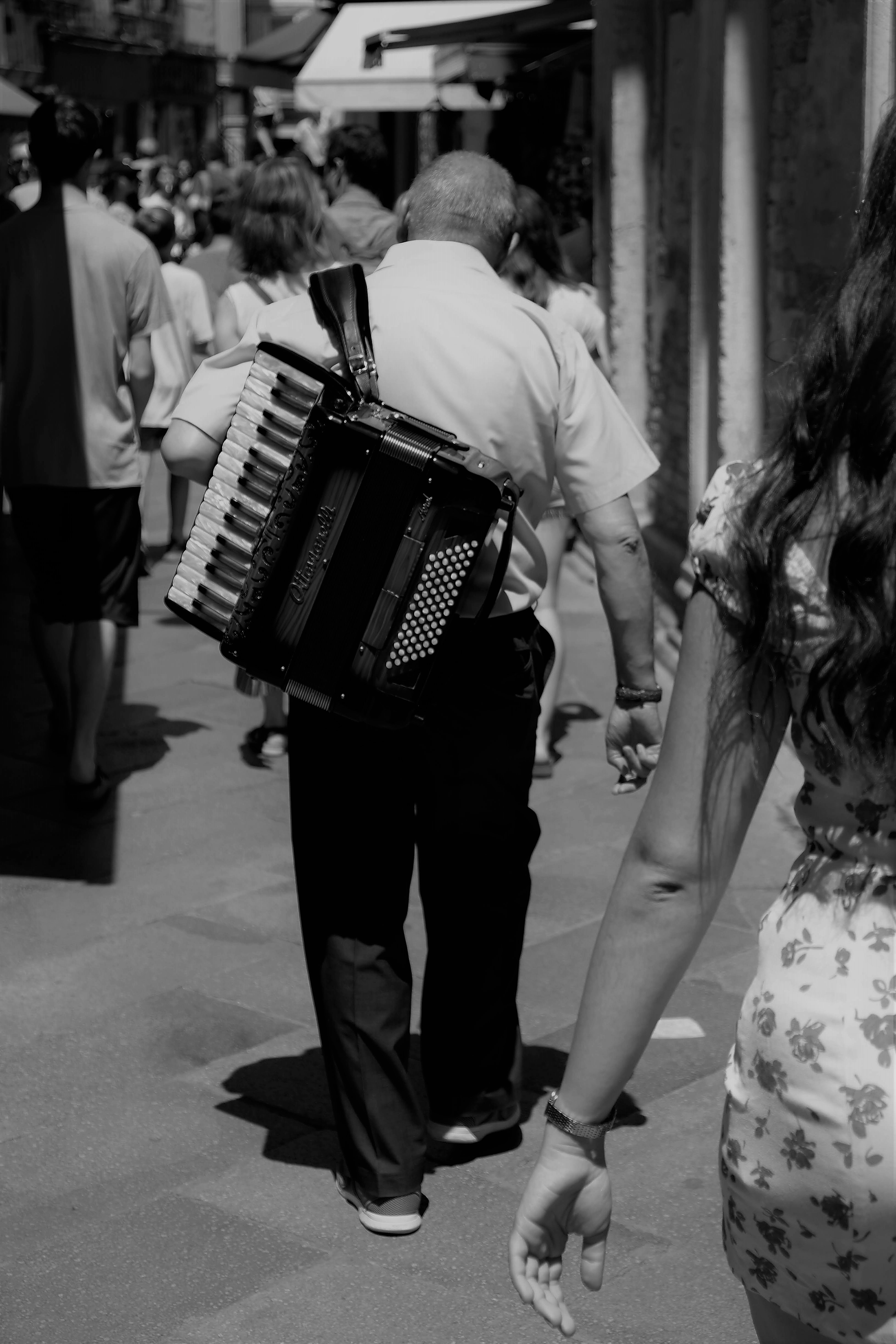 Street Melodies: A Man with an Accordion Walks Through a Crowded Corridor