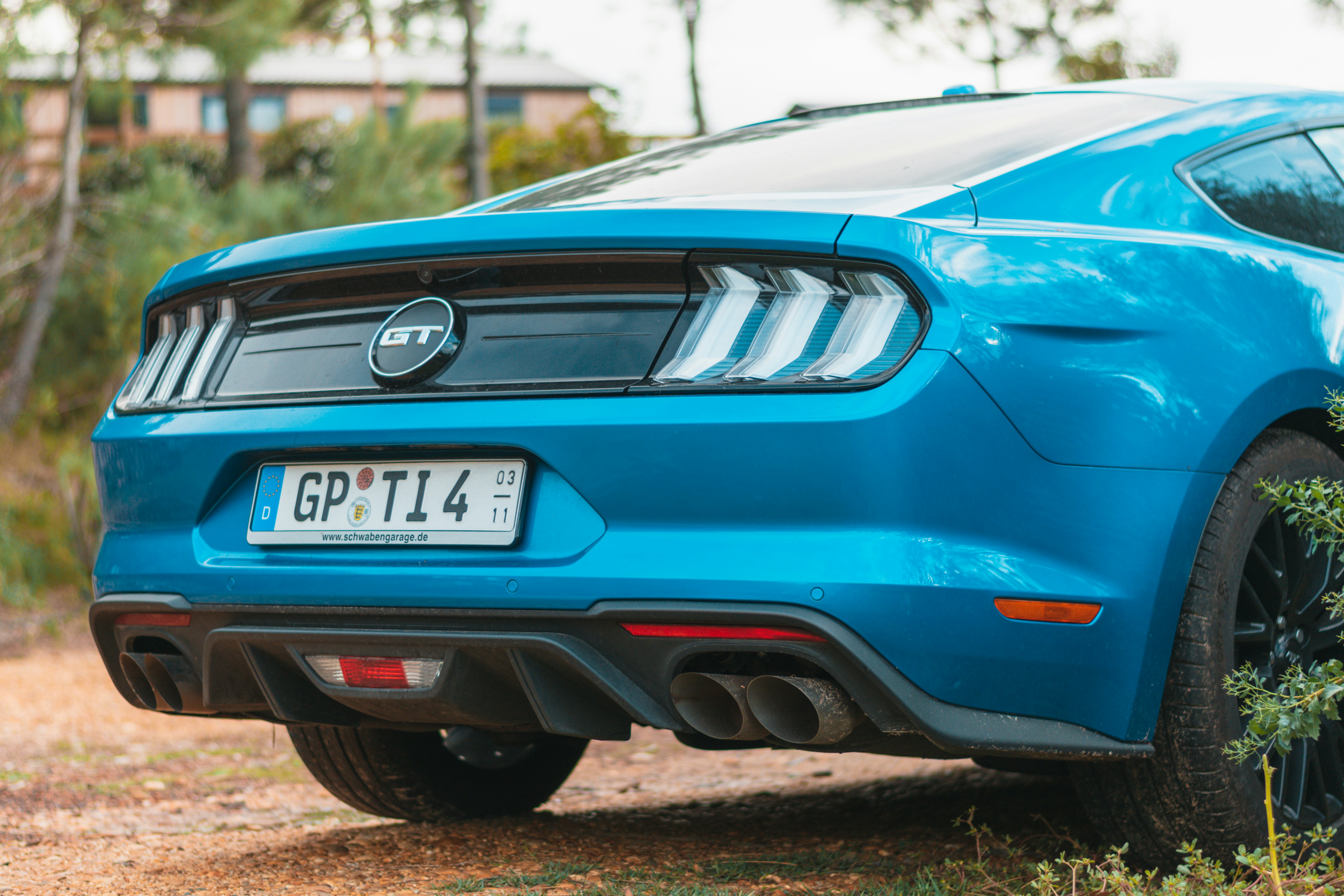 Blue Streak: Rear-Facing View of a Mustang on Gravel