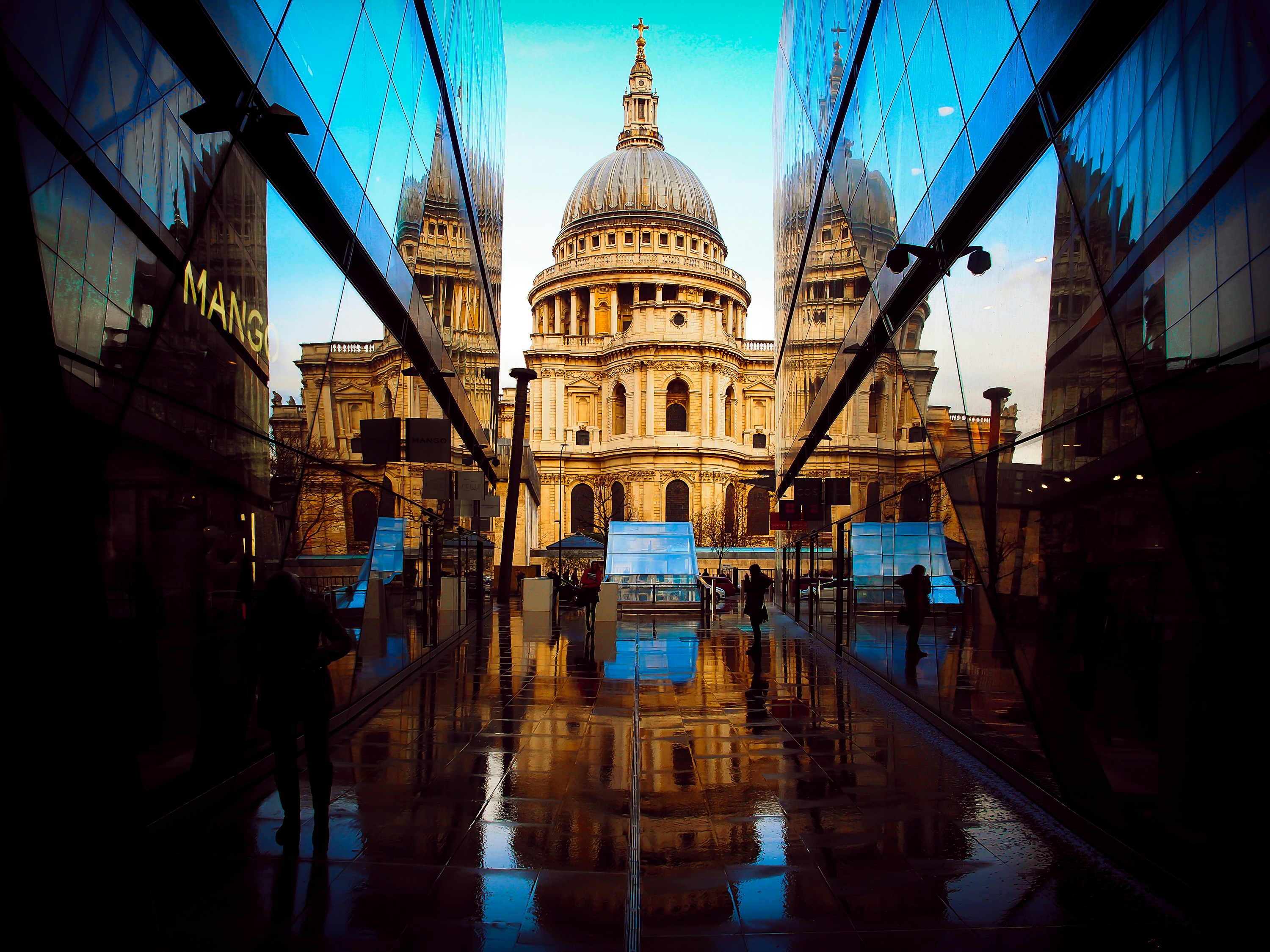St. Paul's Cathedral mirrored in modern glass buildings with a vivid blue sky.