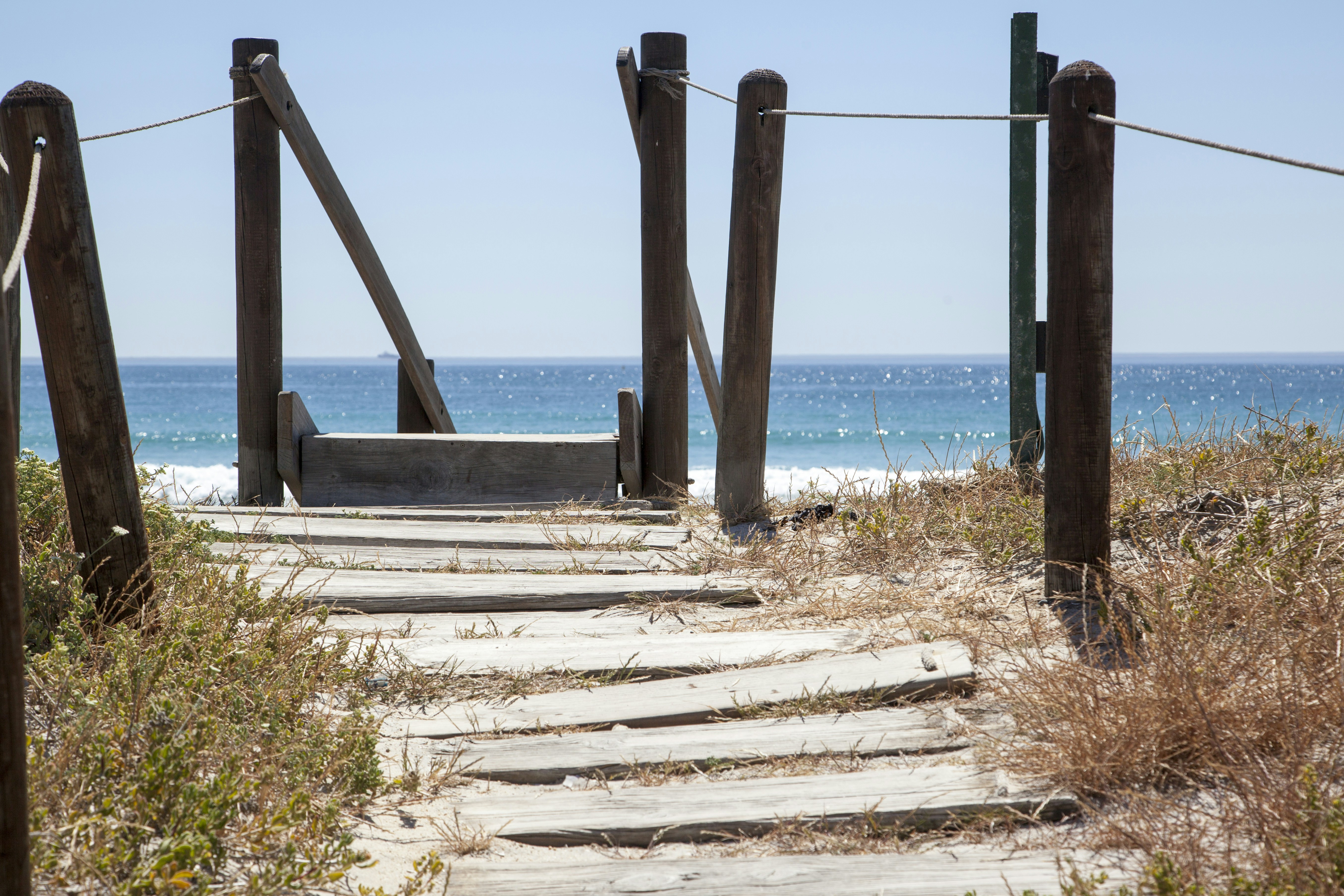 Boardwalk onto beach | brown wooden ladder on white sand near body of water during daytime