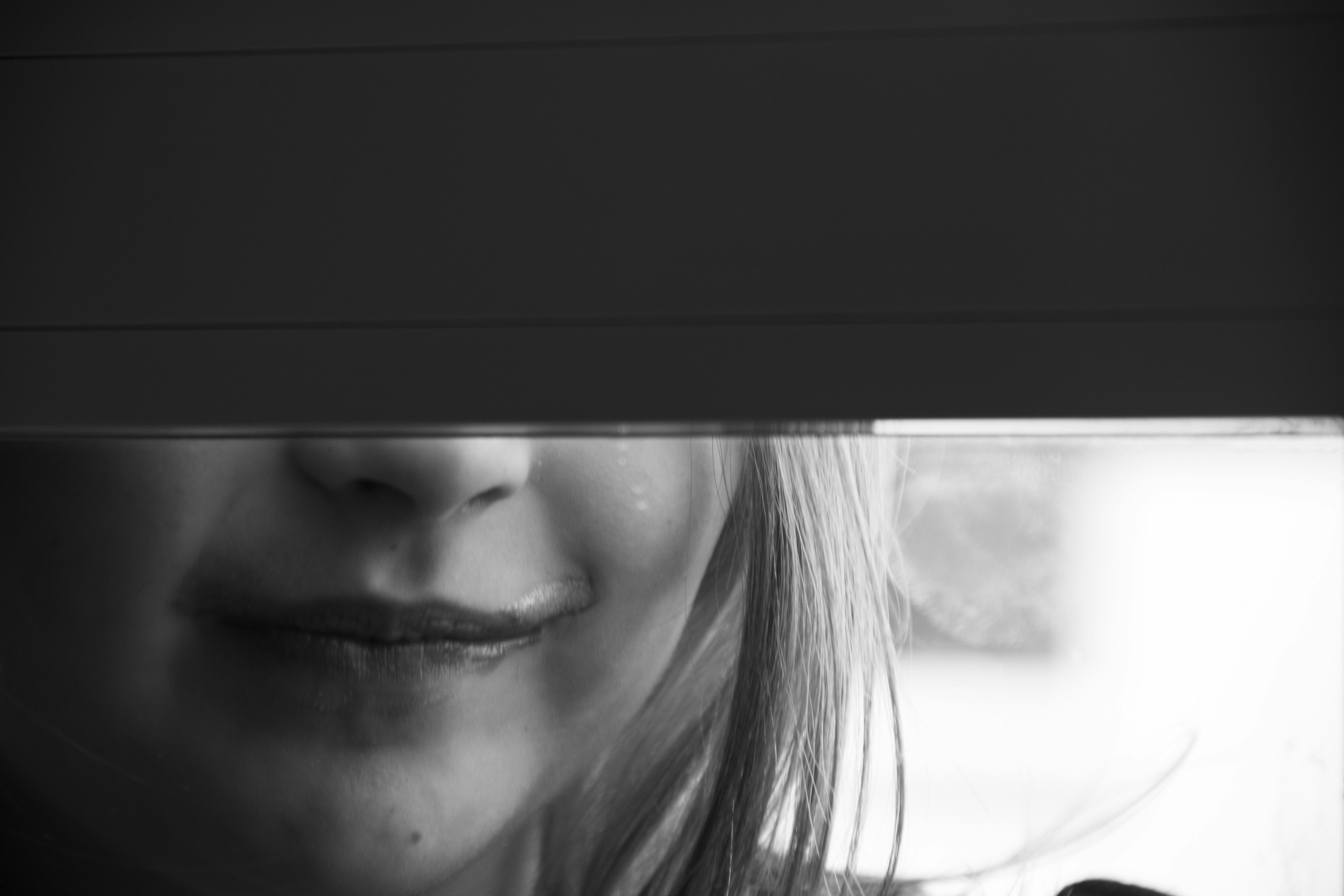 Under the Slat: A Monochrome Close-Up of a Whispered Smile