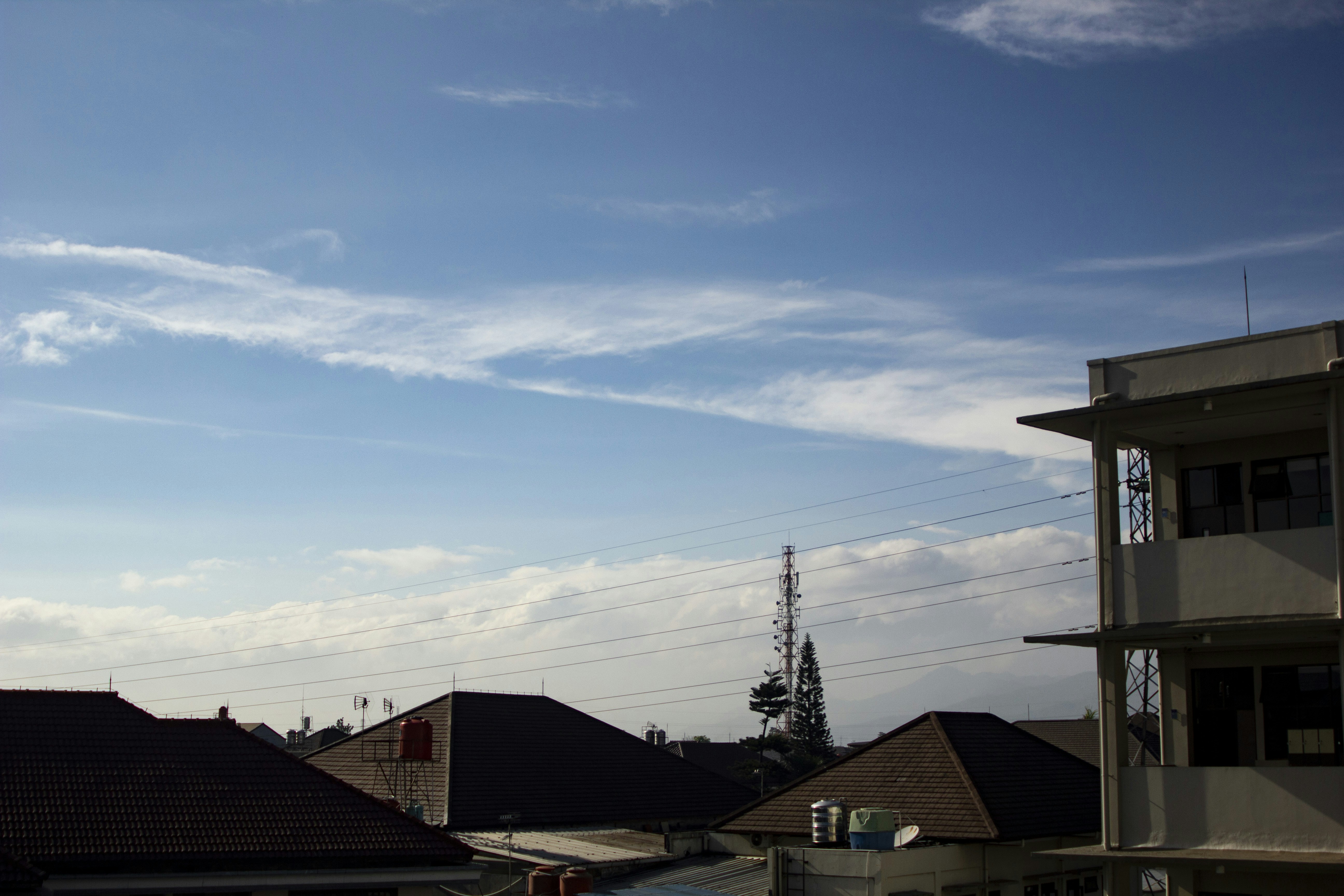 A serene view of rooftops and a clear sky, showcasing the architectural lines of buildings against a backdrop of soft clouds. 