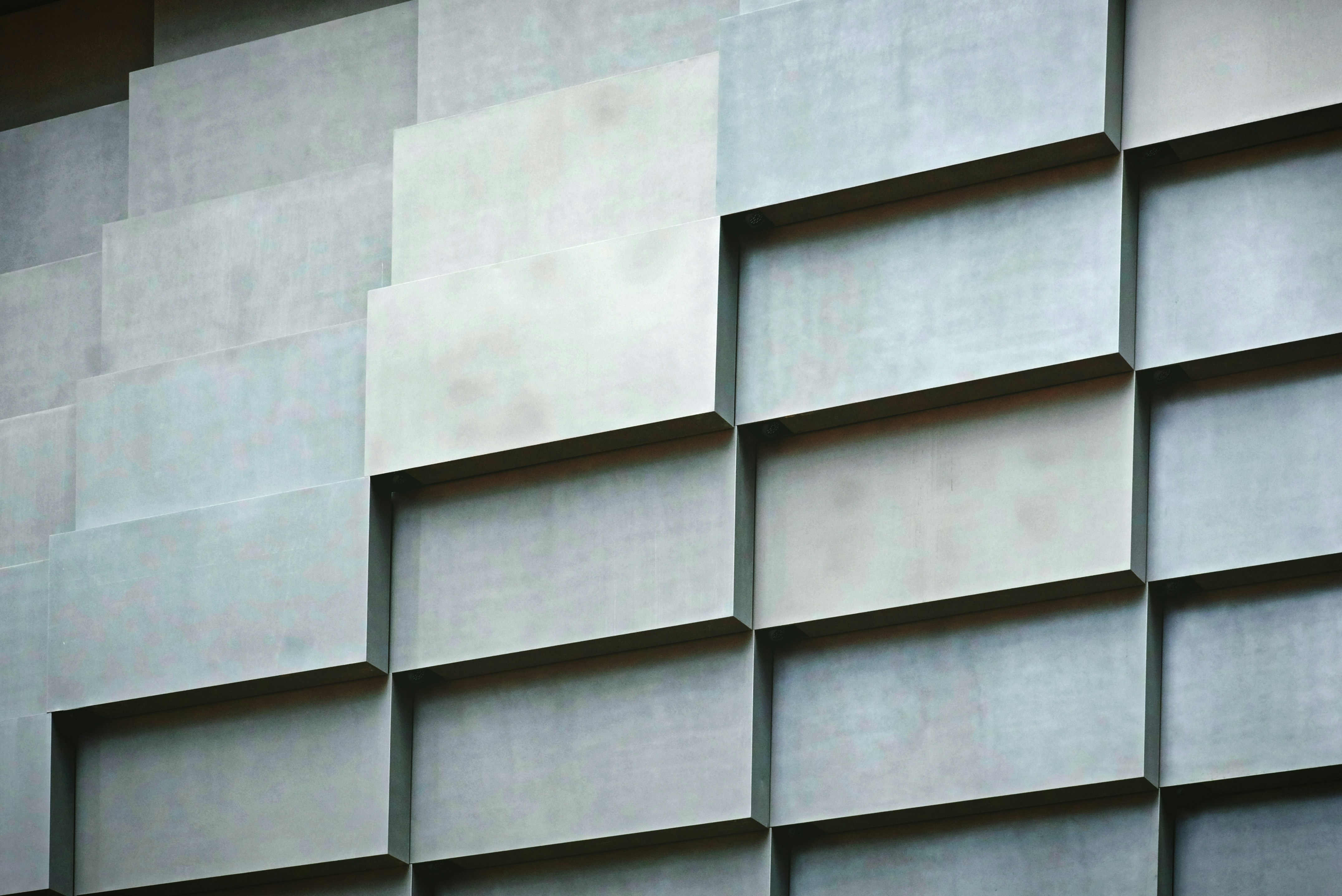 Abstract architectural facade featuring a series of textured, overlapping panels in muted tones.