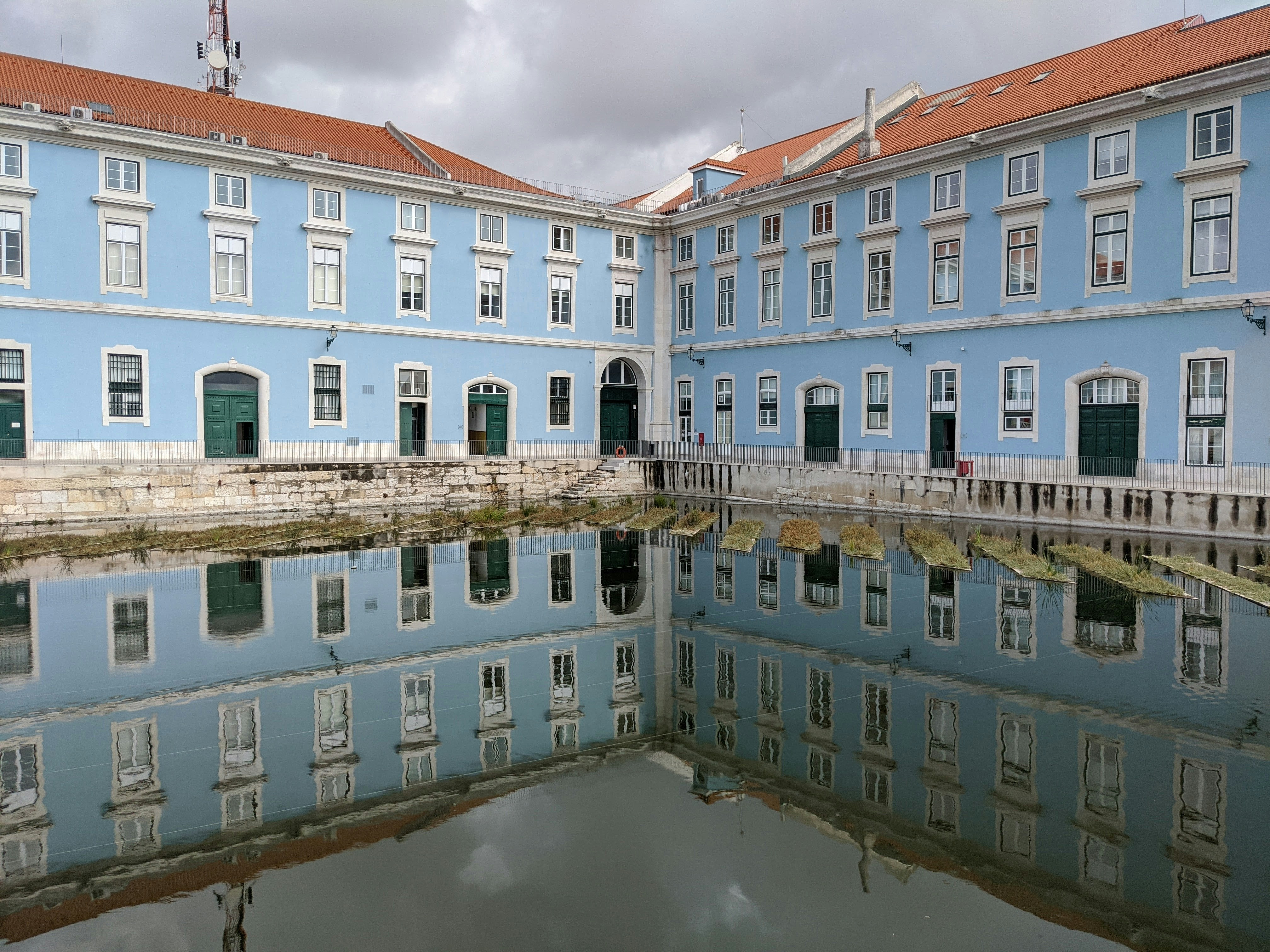 Historic blue buildings mirrored in still water, showcasing a serene urban landscape.