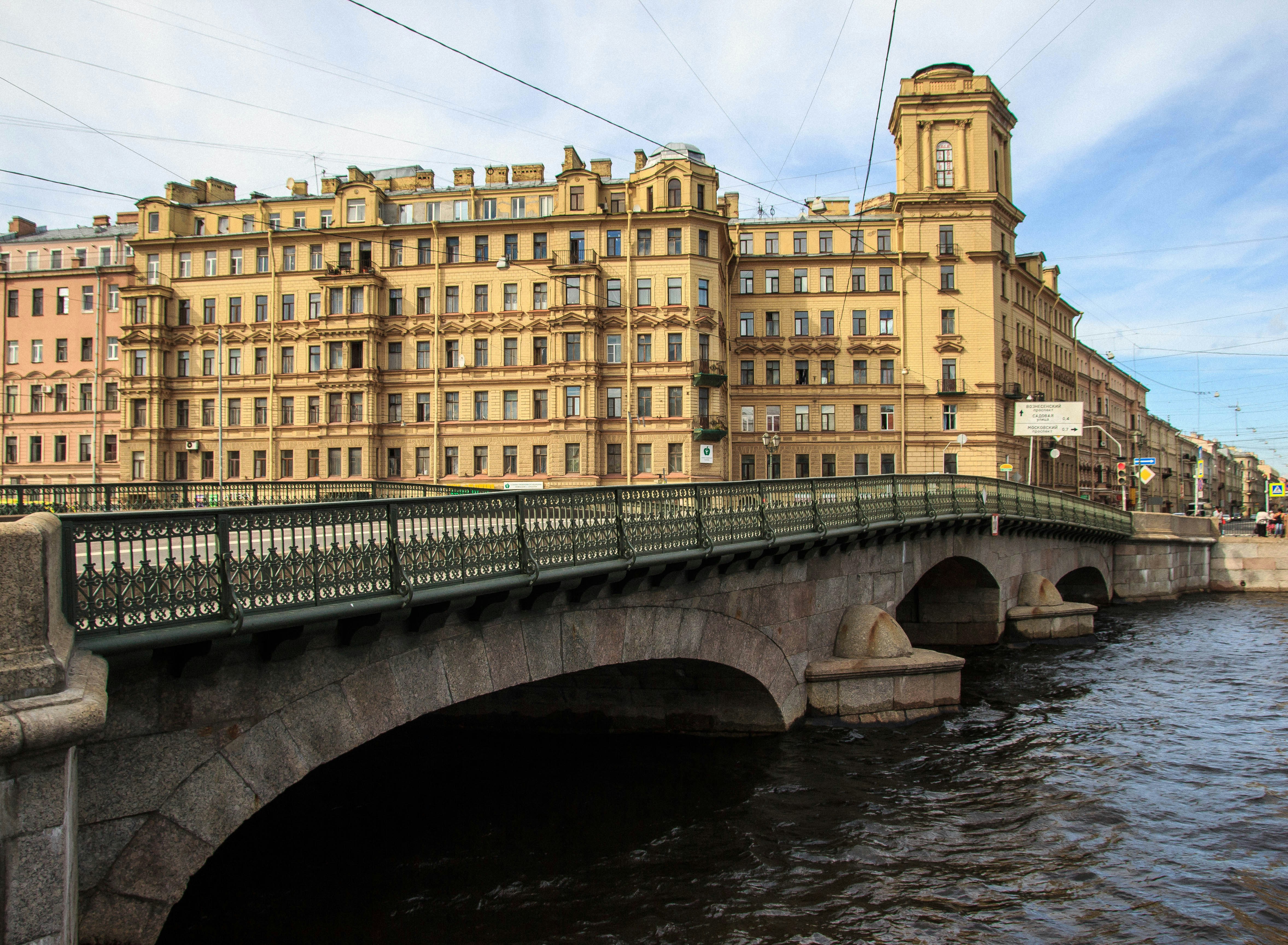 Stone bridge spanning a river with a backdrop of ornate historic buildings under a clear sky.