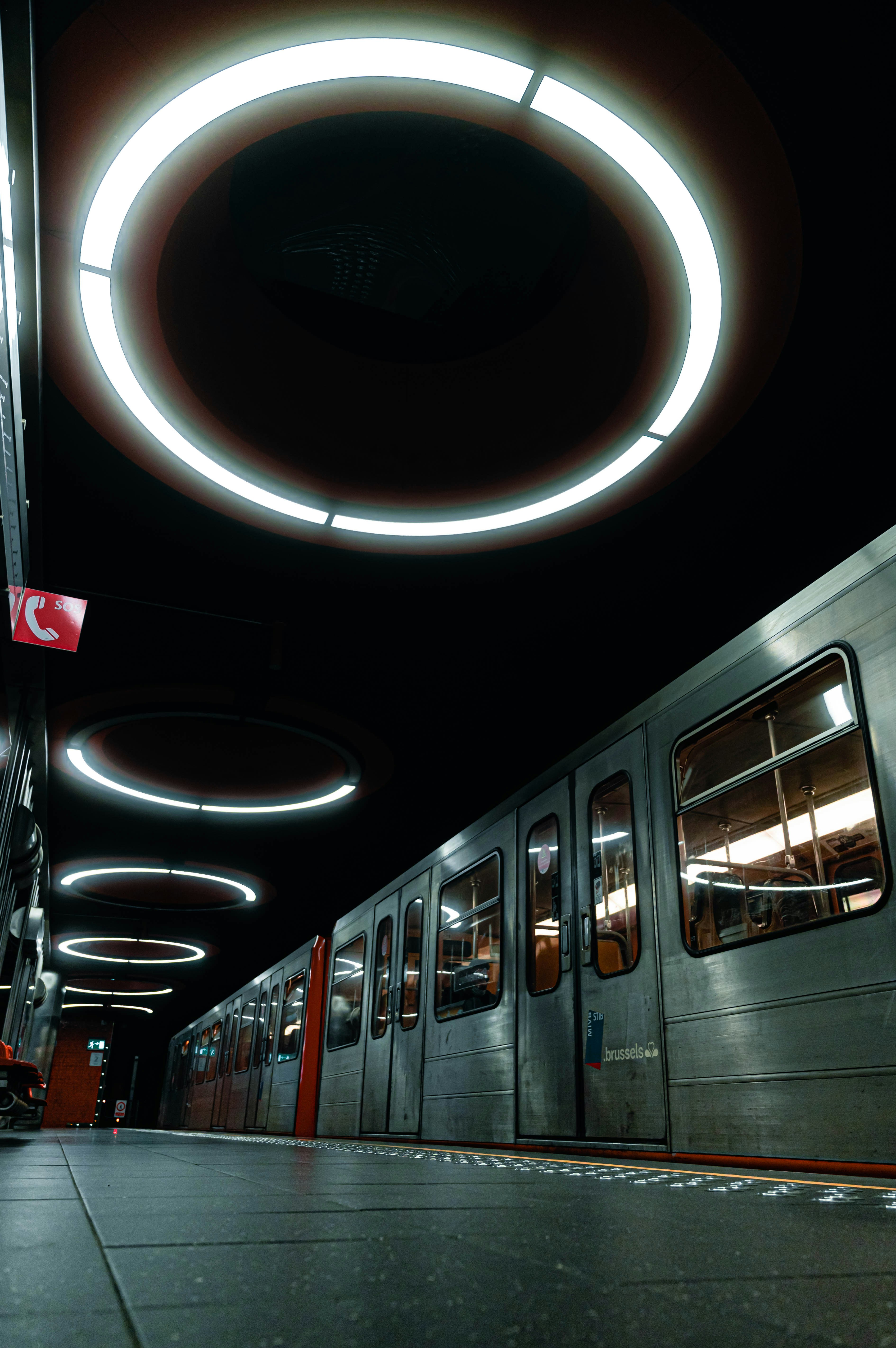 Modern subway platform illuminated by circular overhead lights, showcasing a sleek train waiting at the station.