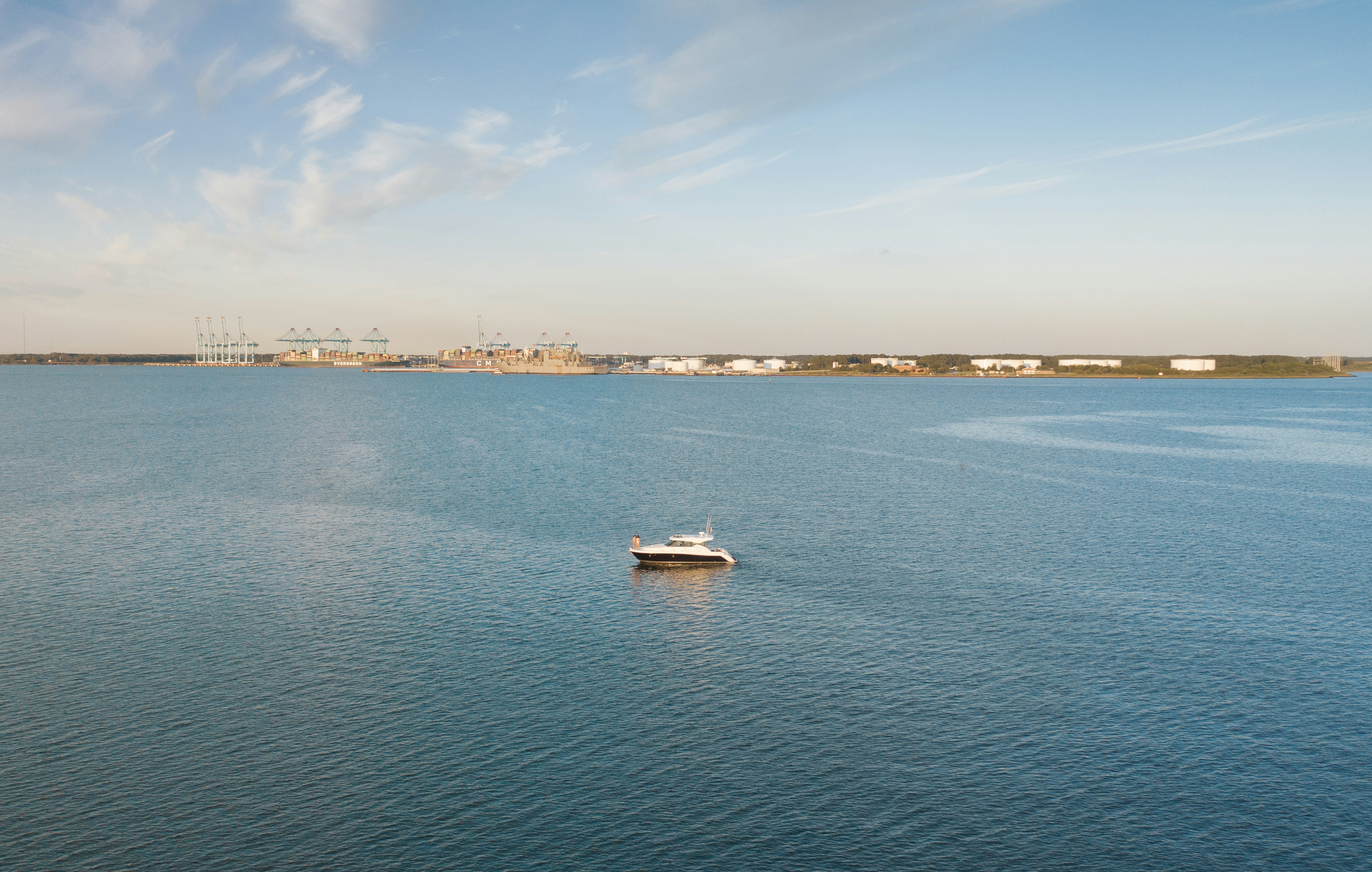 White boat sailing on a vast blue sea beneath a clear sky.