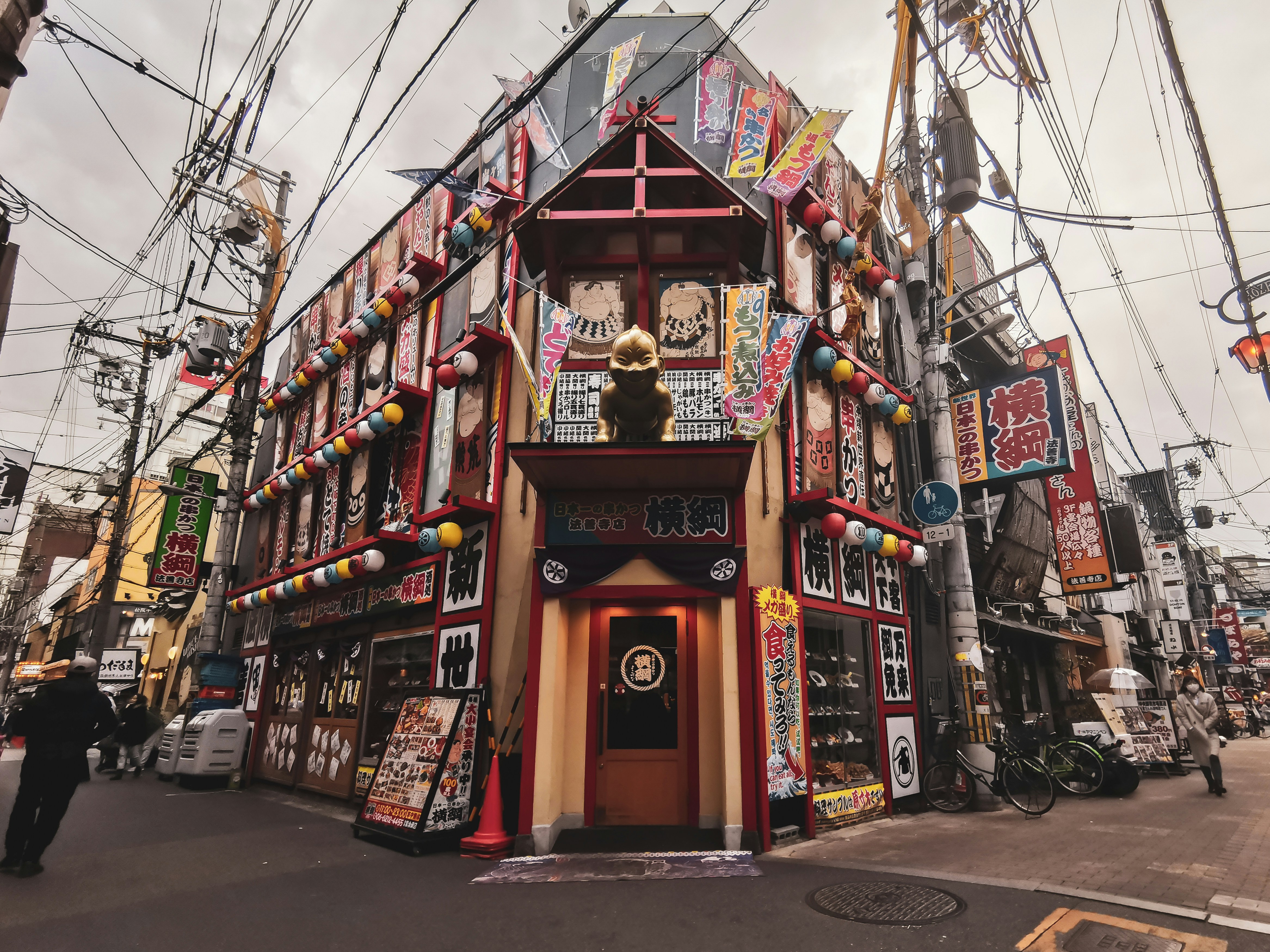 Lantern-Lit Corner: A Bustling Street Portrait of a Red-Trimmed Eatery