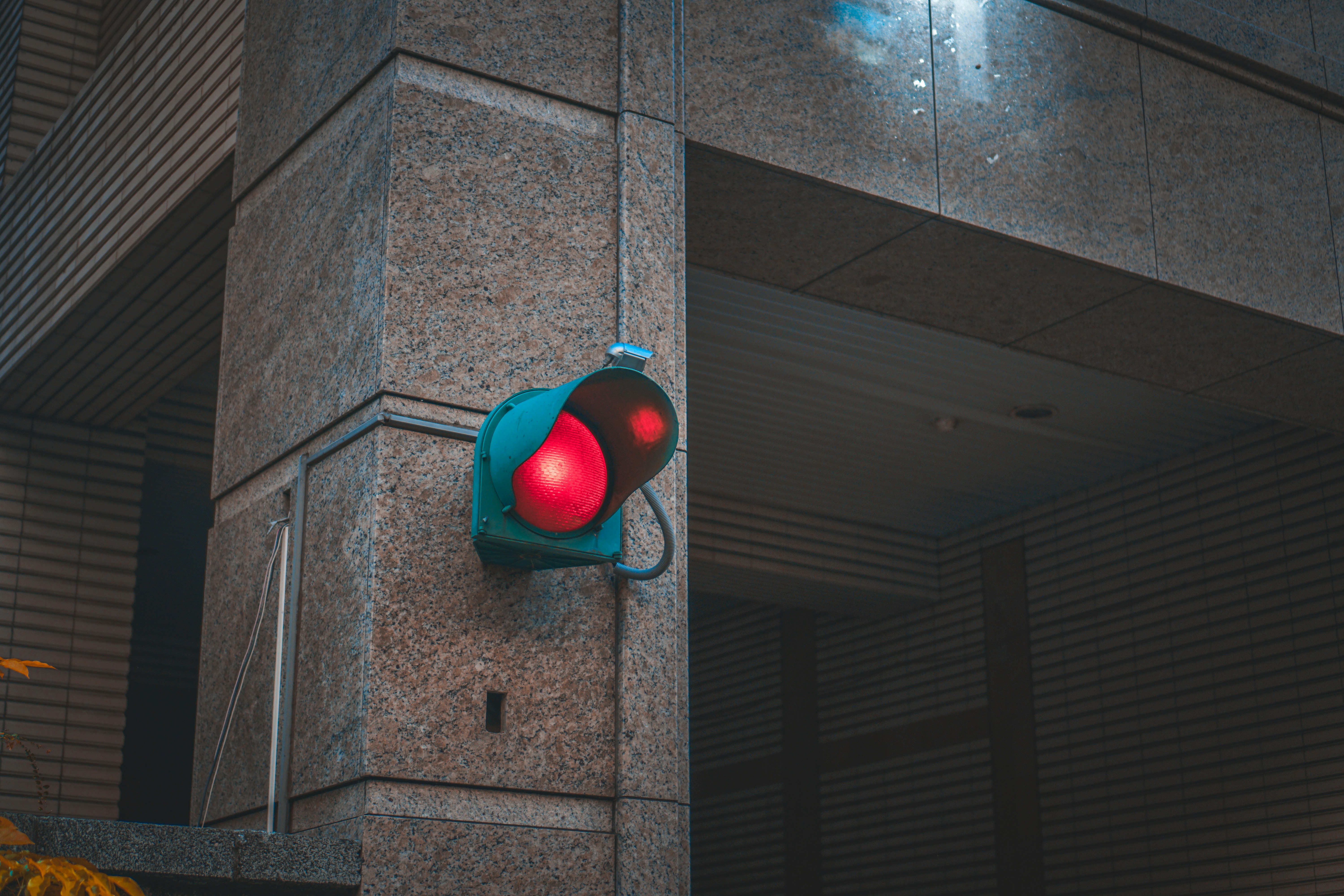 Teal Signal at the Granite Corner: A Red Light in Quiet Urban Facade