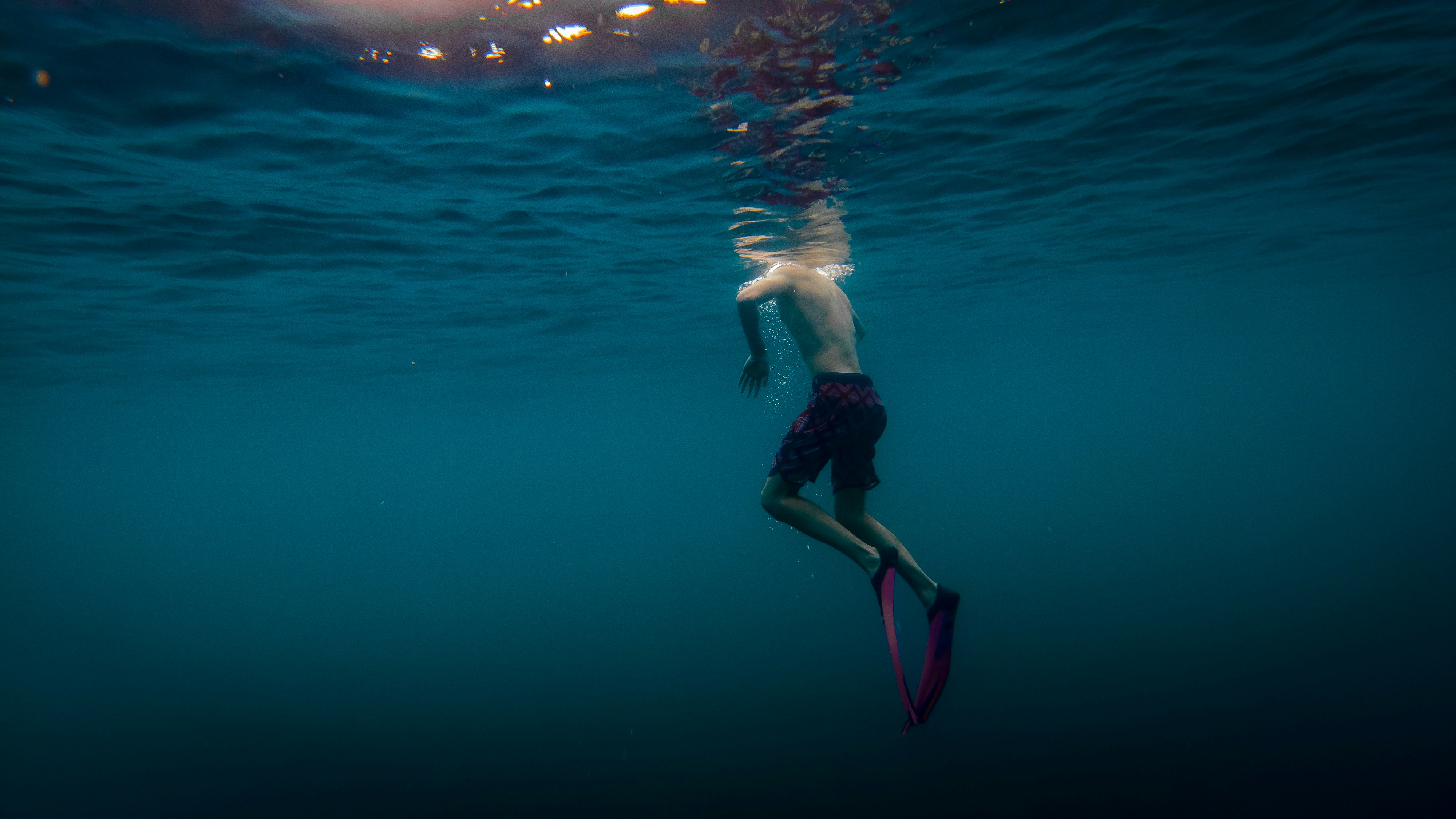 A young swimmer glides through the tranquil underwater world, surrounded by shimmering bubbles and soft light filtering from above.