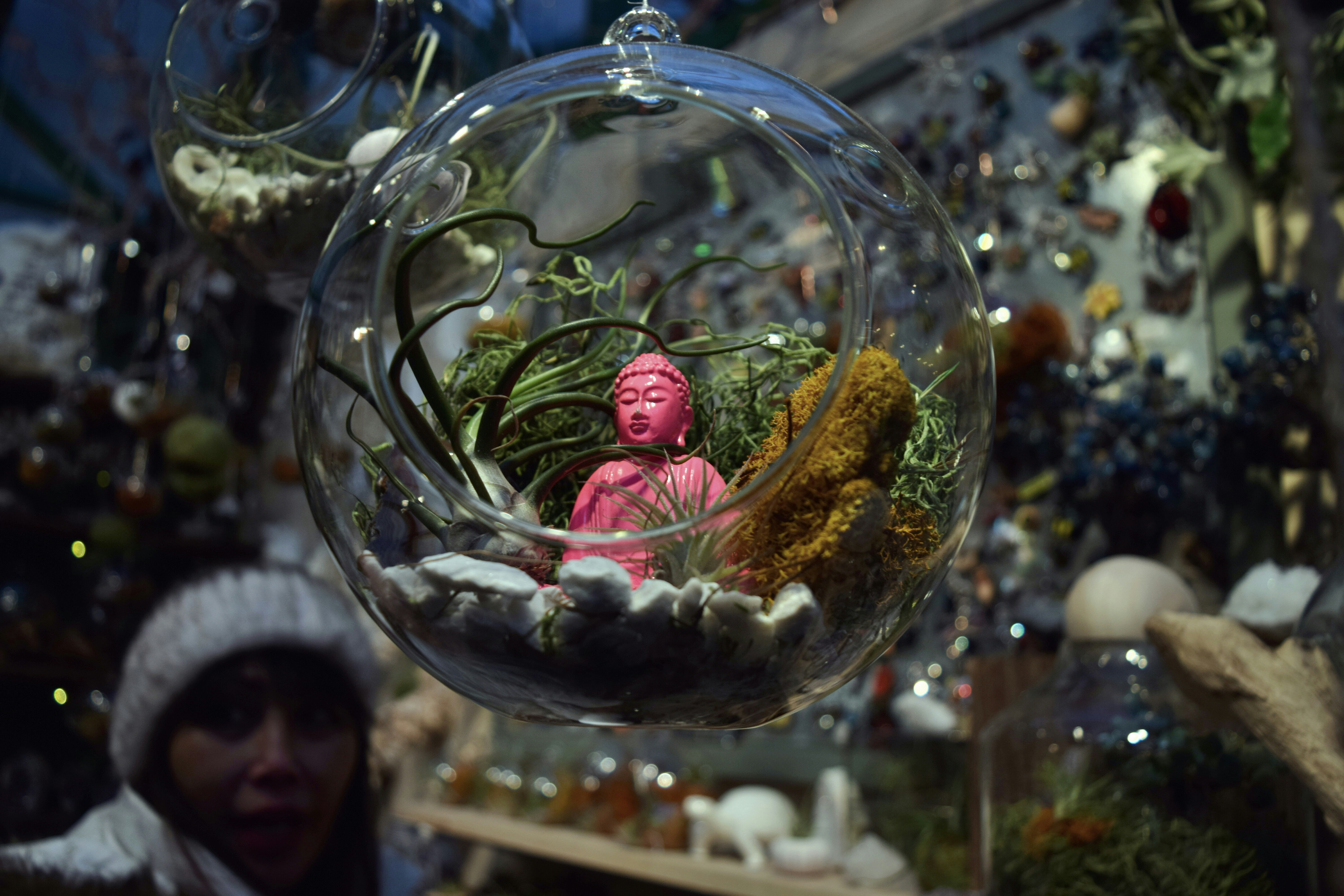 Floating Glass Dome: Pink Buddha Ornament in a Winter Workshop