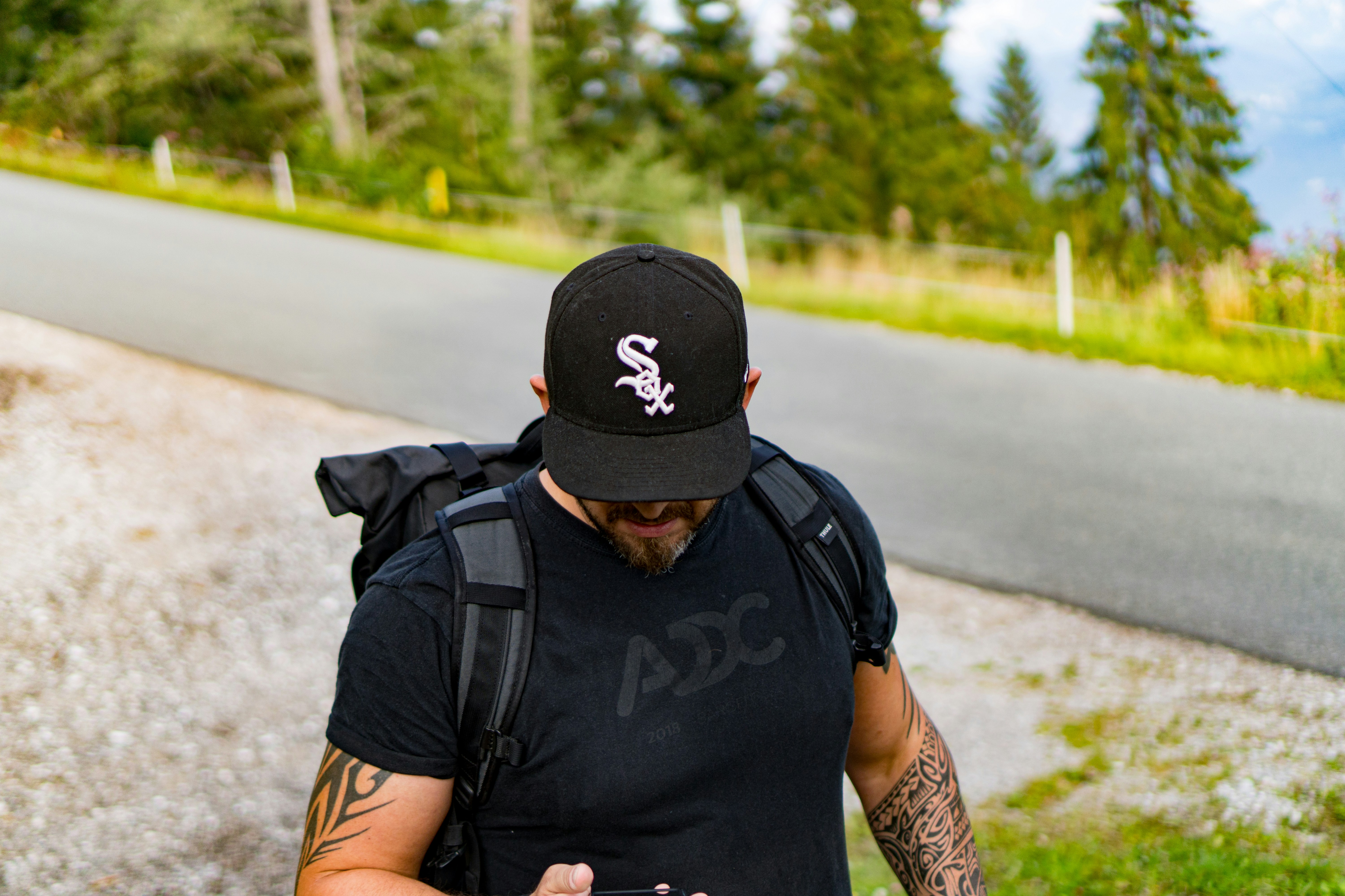 Man checks directions on his smartphone while hiking on a scenic mountain path.