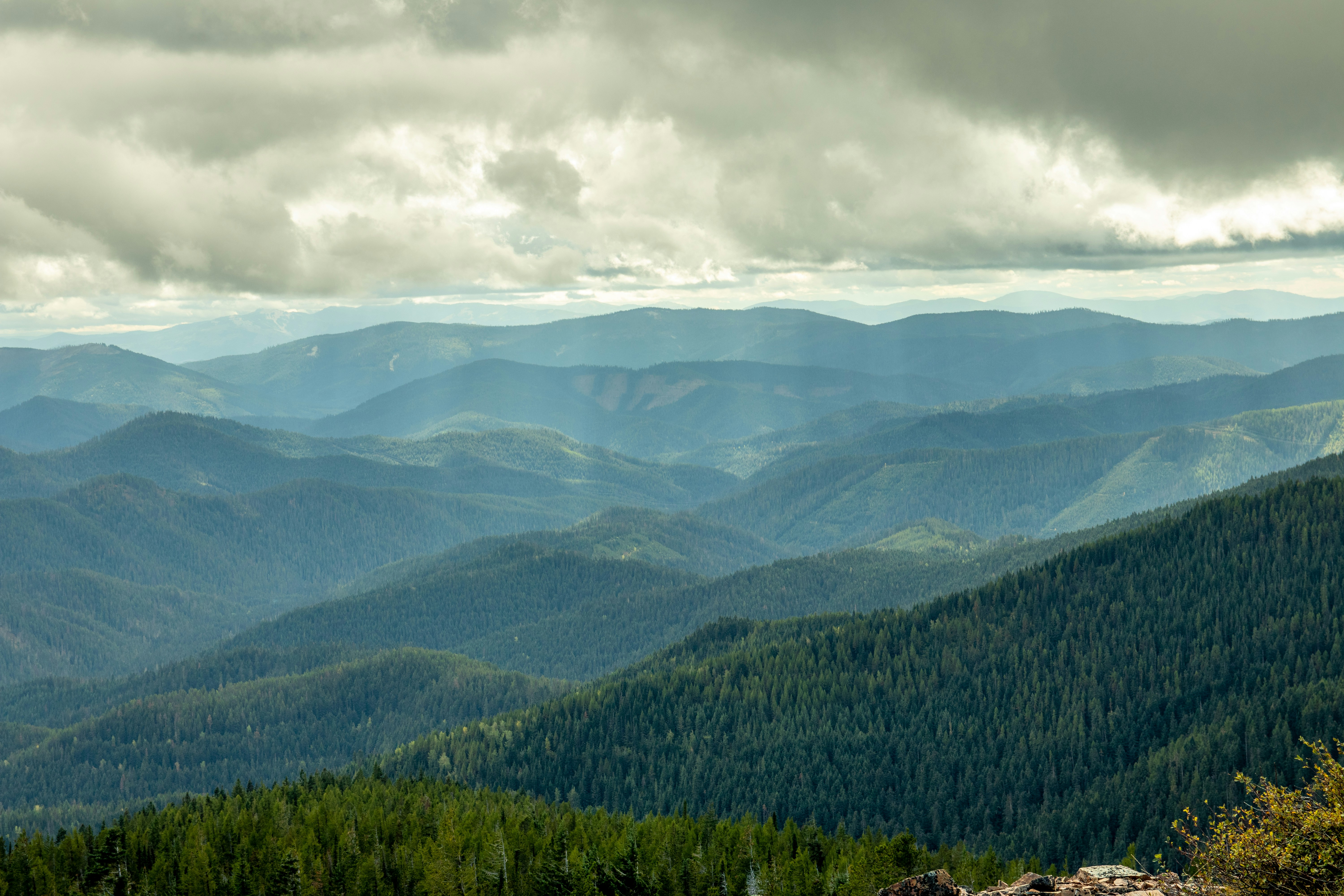 Rolling green mountains under a dramatic sky with dense clouds.