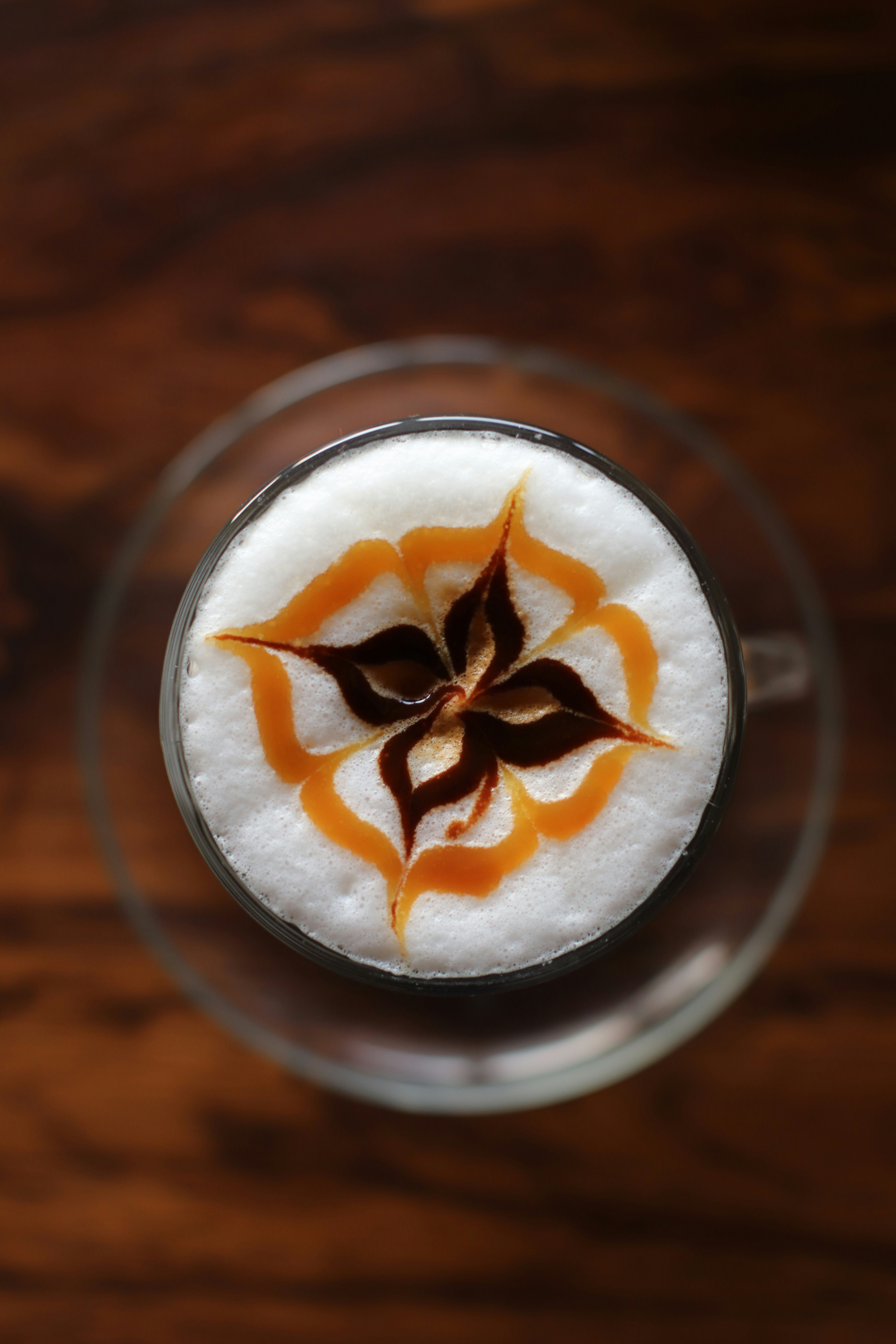 Star-Petal Latte Art in a Glass on a Warm Wooden Counter