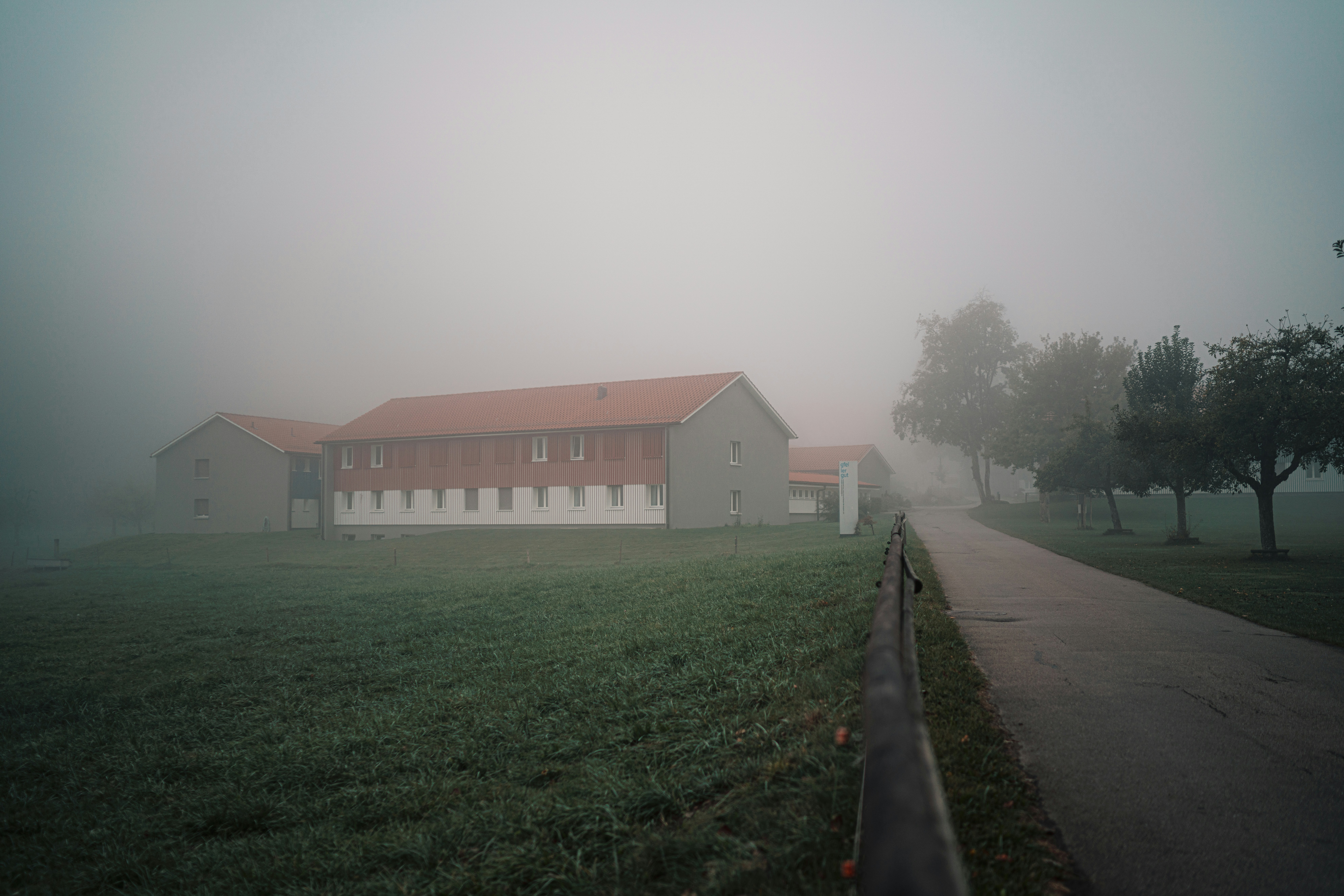 Veiled Farm: A Red-Roofed Structure Emerges Through Dense Fog