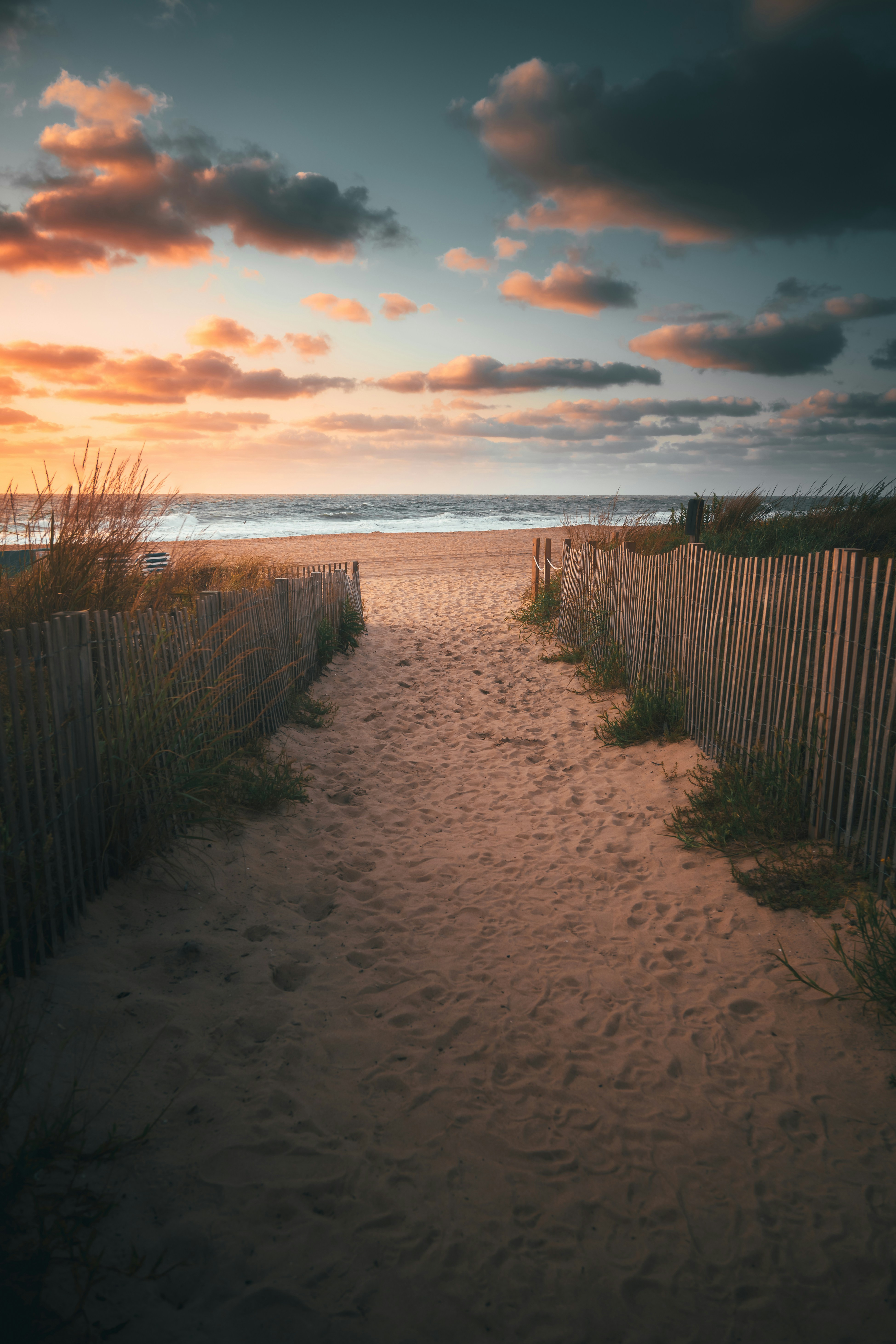 Walkway to the beach on a summer morning in Ocean City, Maryland | brown wooden fence on brown sand near body of water during daytime