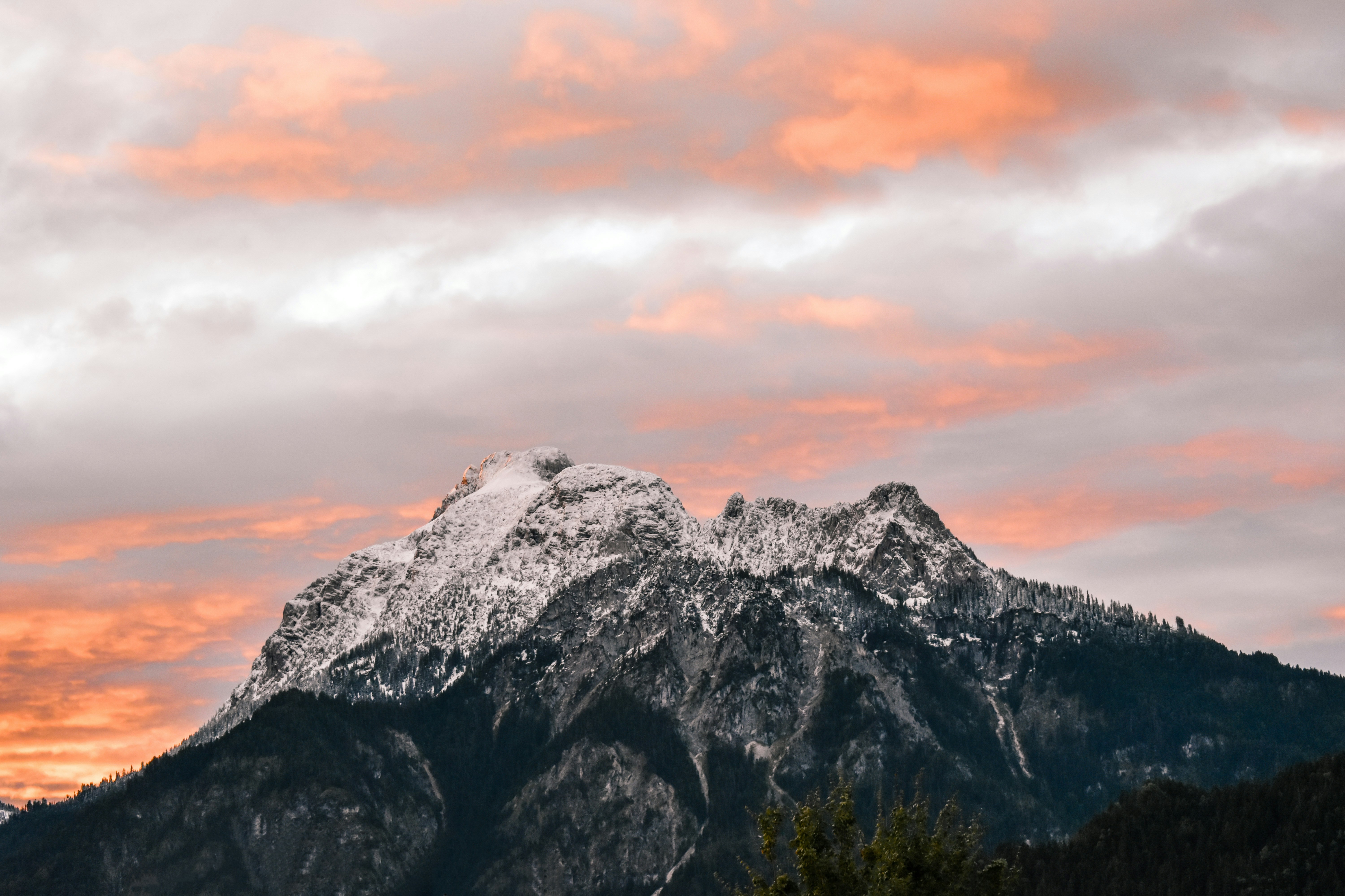 Majestic snow-capped mountain under a sky painted with vibrant sunset hues.