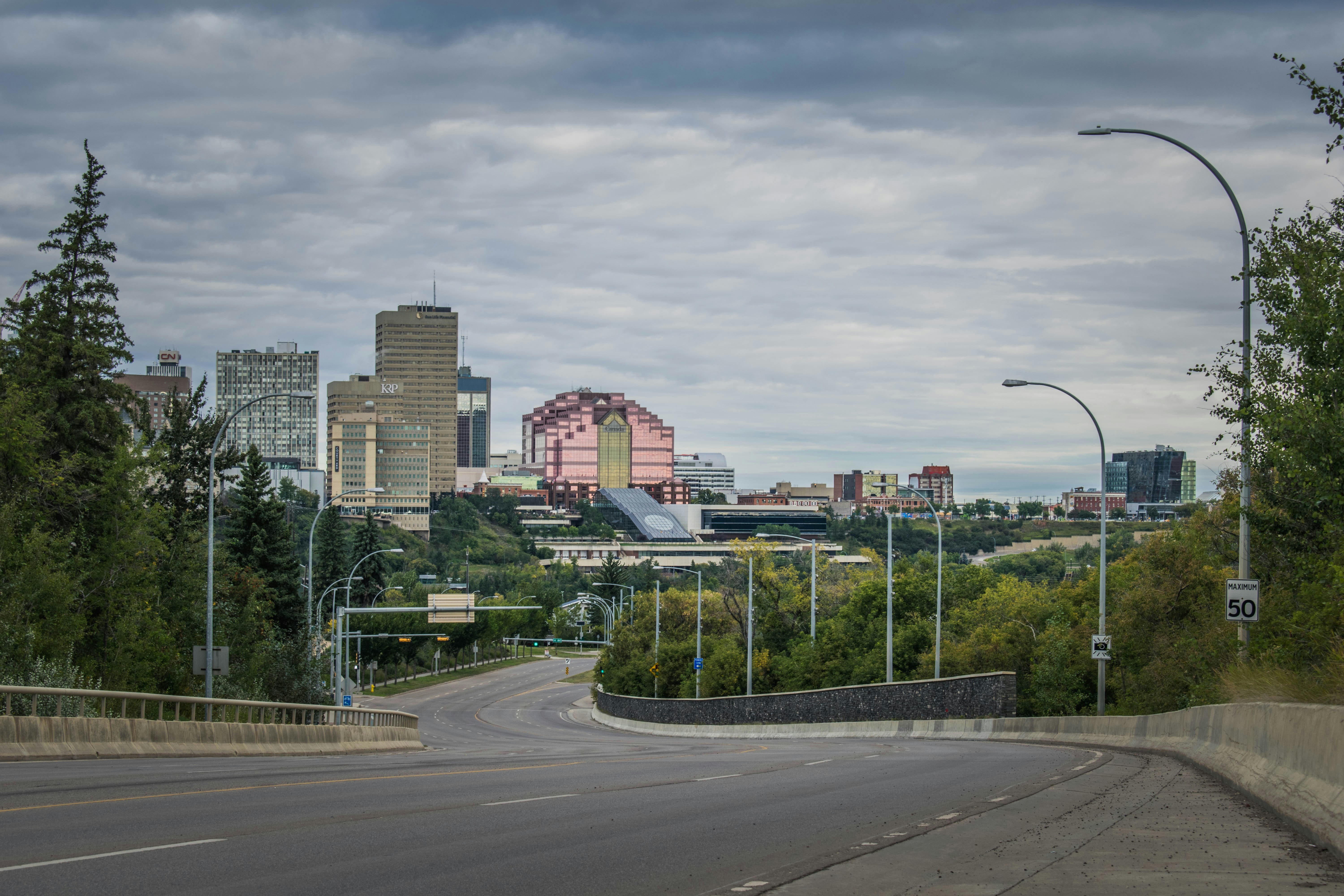 City skyline with diverse architecture framed by lush trees and an overcast sky.
