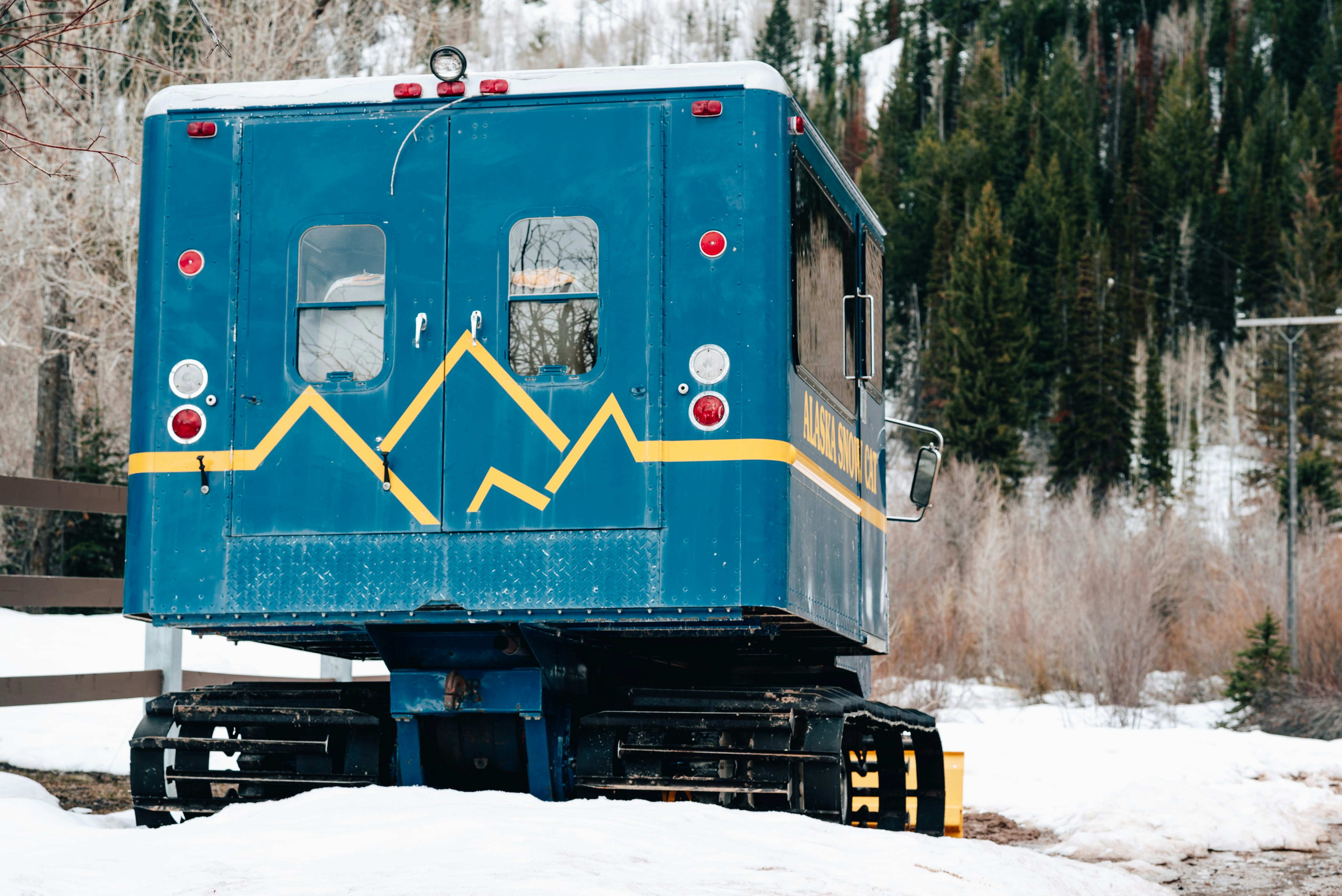 Blue Snowcat with Mountain-Motif on a Snowy Track