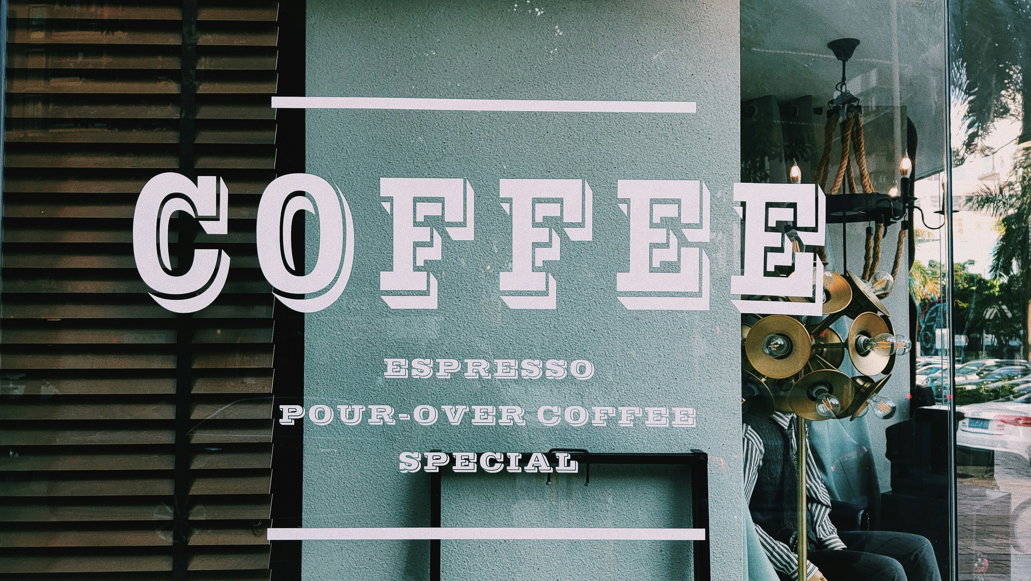 Stylized coffee shop window displaying the word 'COFFEE' along with espresso and pour-over coffee specials.